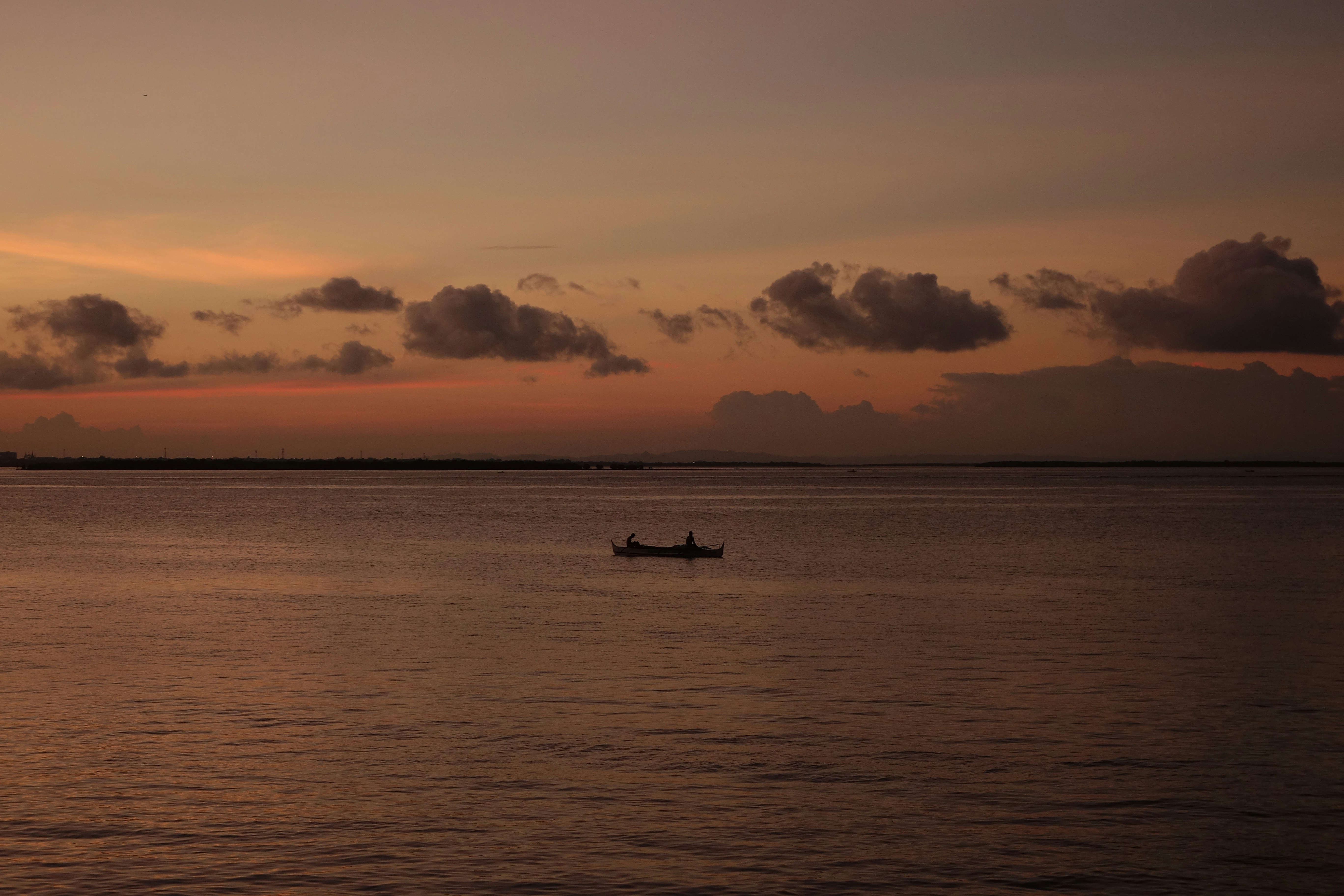 Silhouetted Boat at Dusk on a Calm Horizon