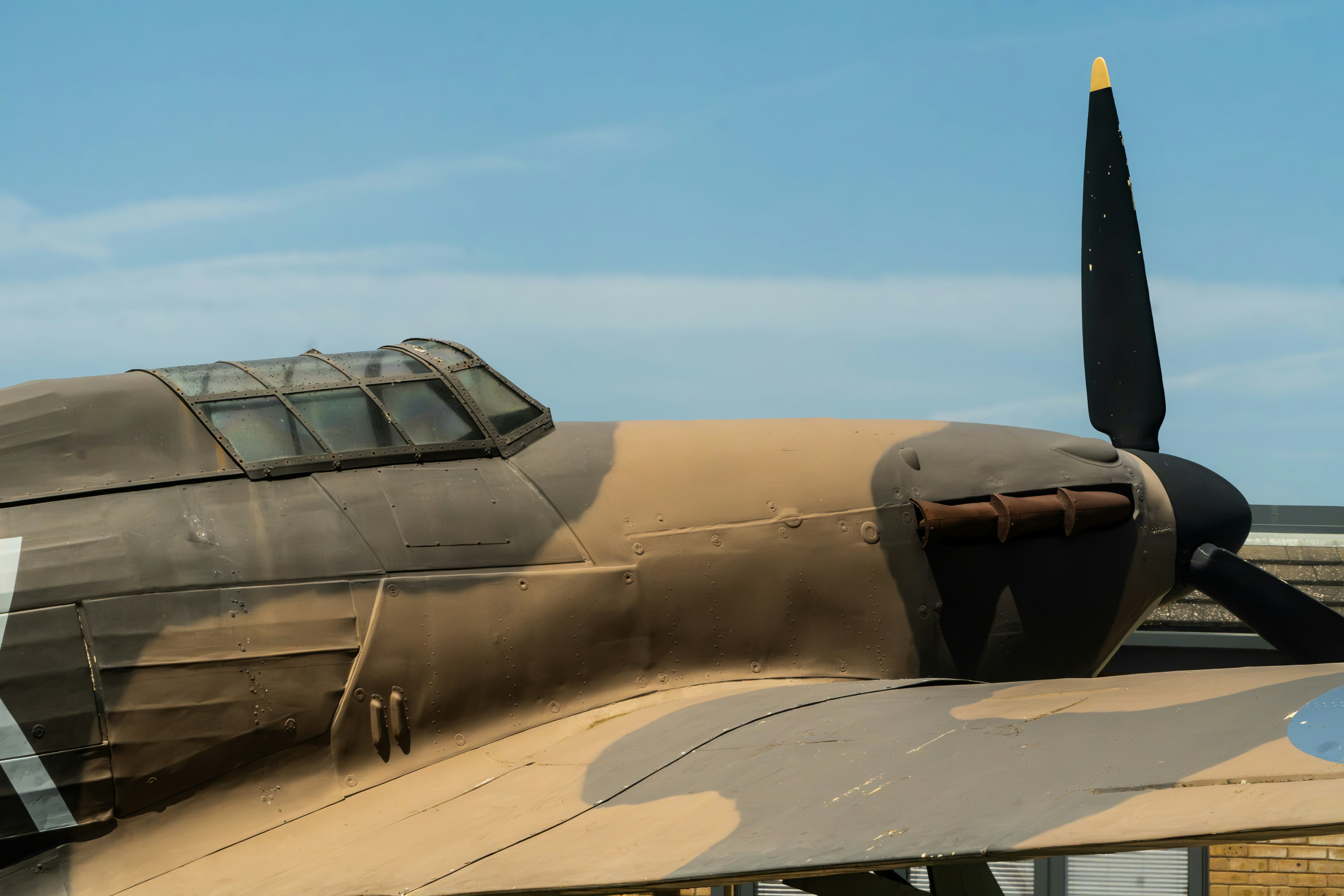 Desert-Toned Warbird: Close-Up of a Vintage Fighter's Fuselage and Propeller
