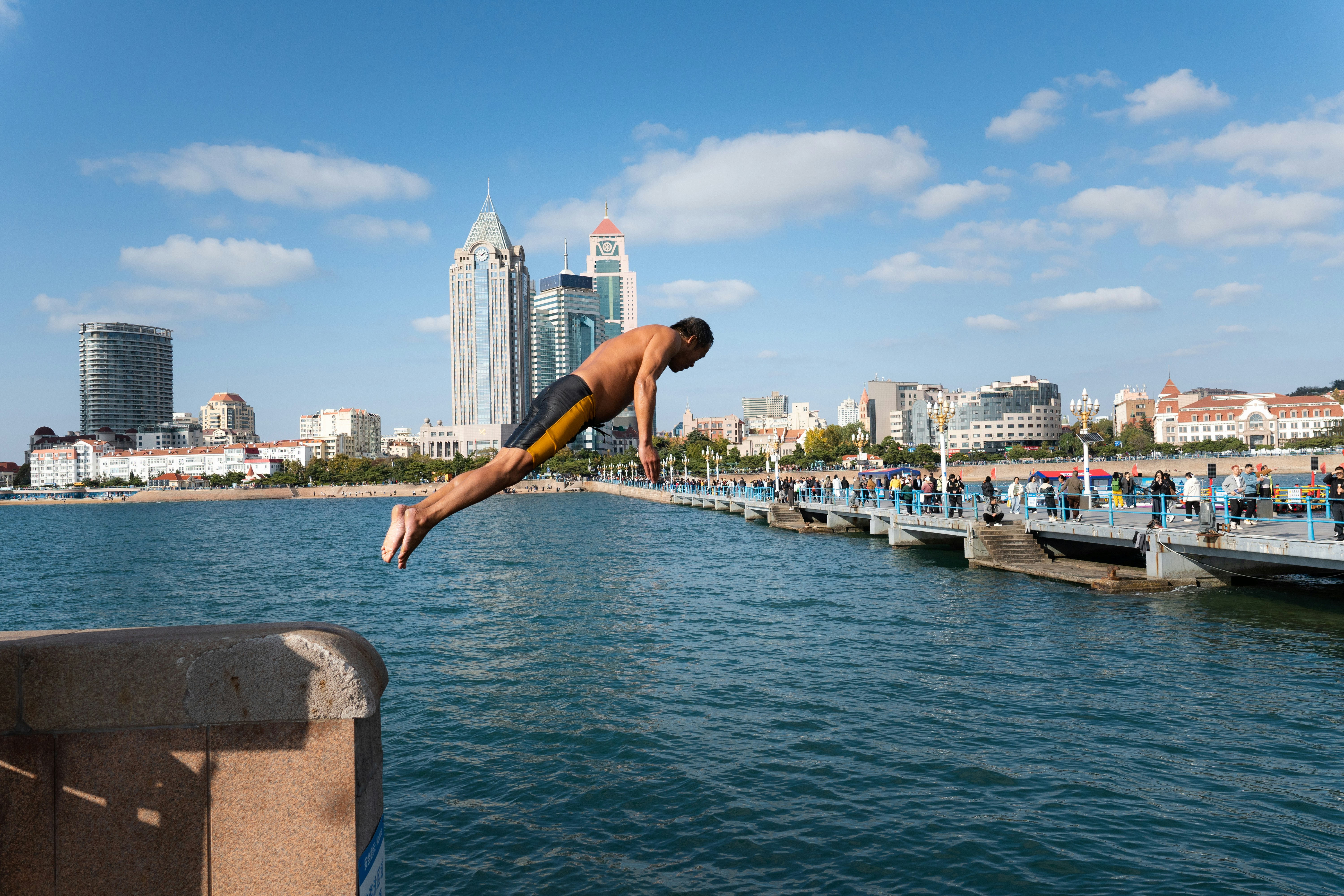 Diving Off the Pier: A Splash of Freedom Against a Cityscape