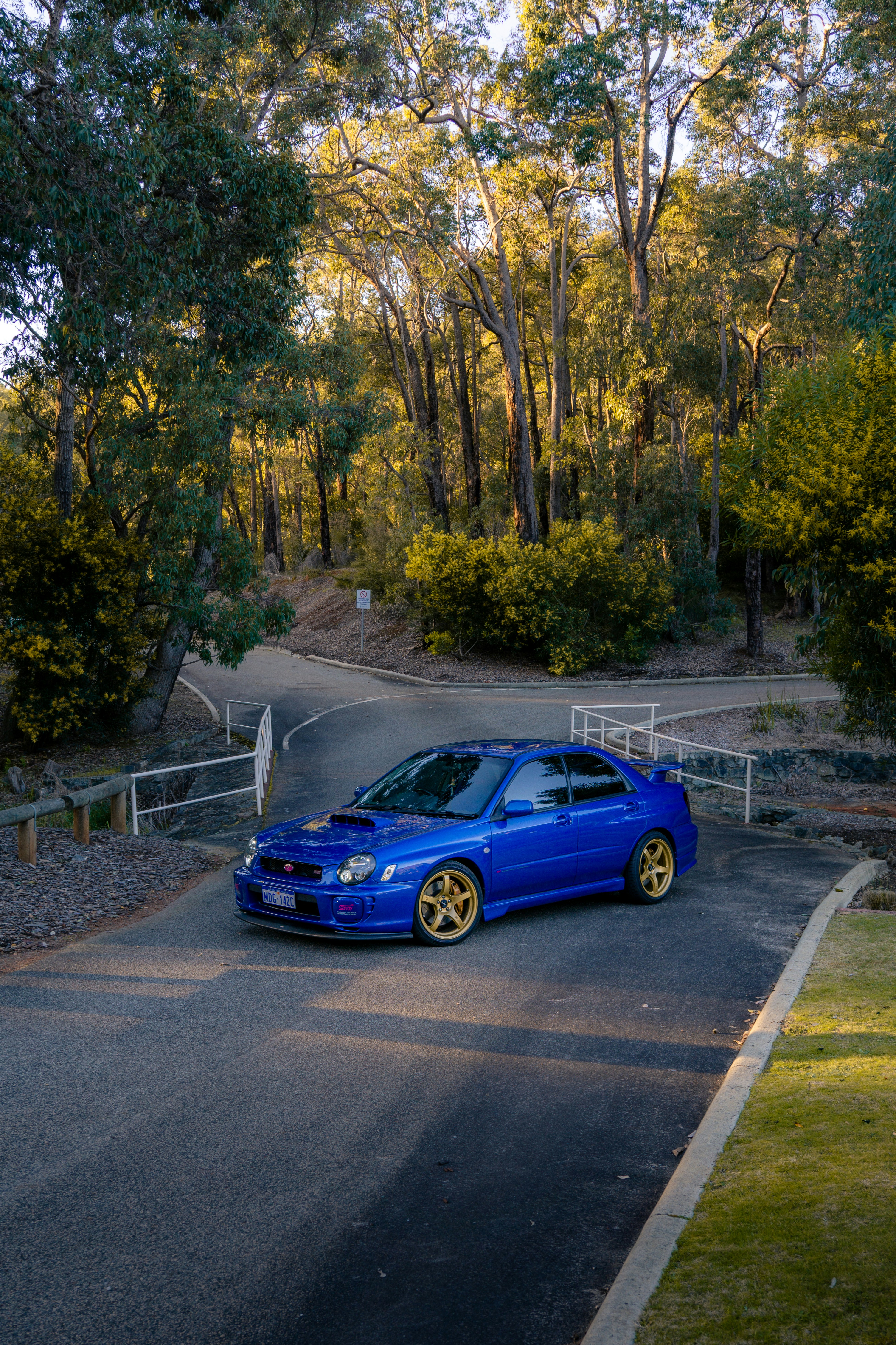 Blue Hue on the Bend: A Neon-Blue Subaru Resting at a Windy Summit