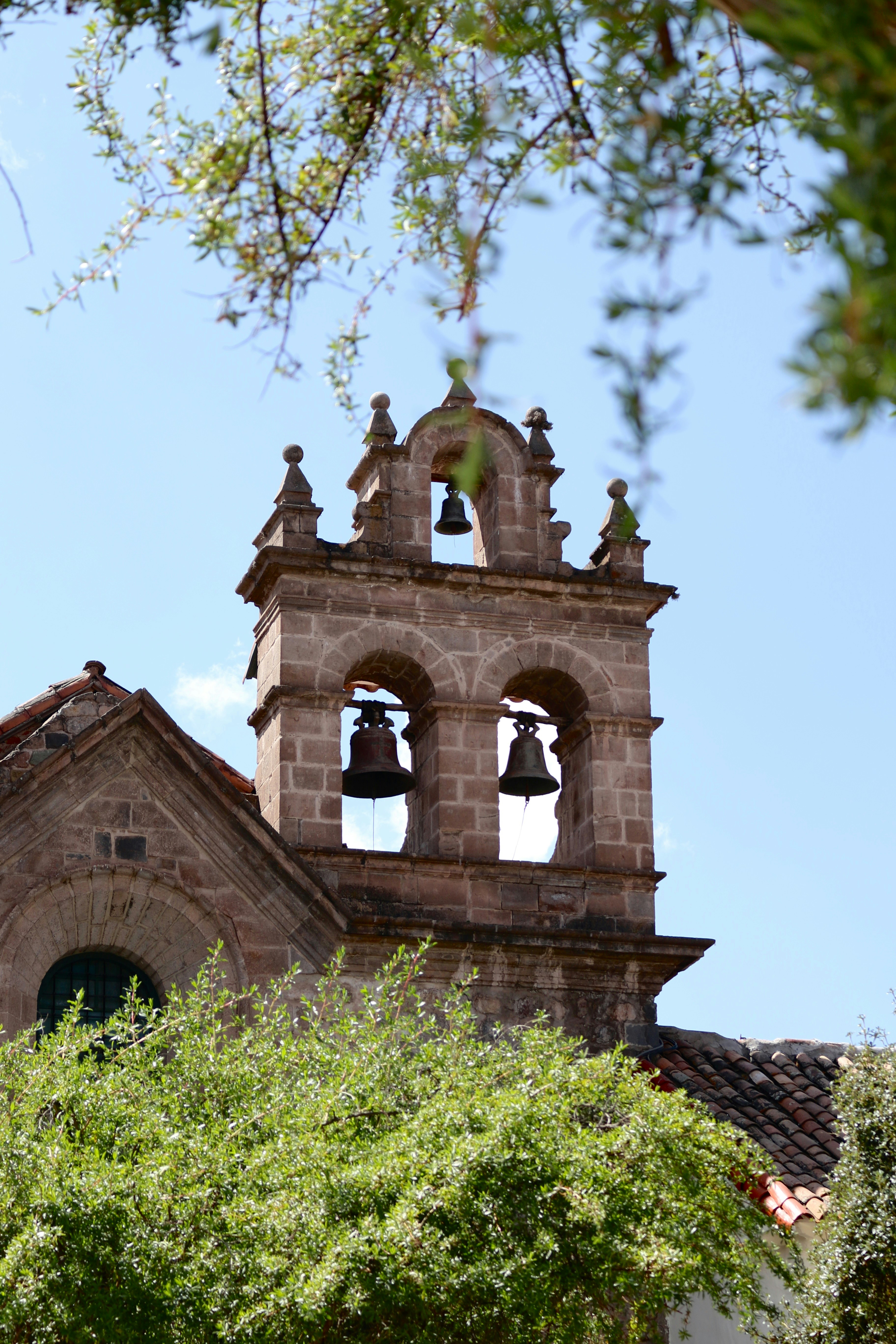 Stone Bell Tower Rising Above Greenery Under a Clear Sky