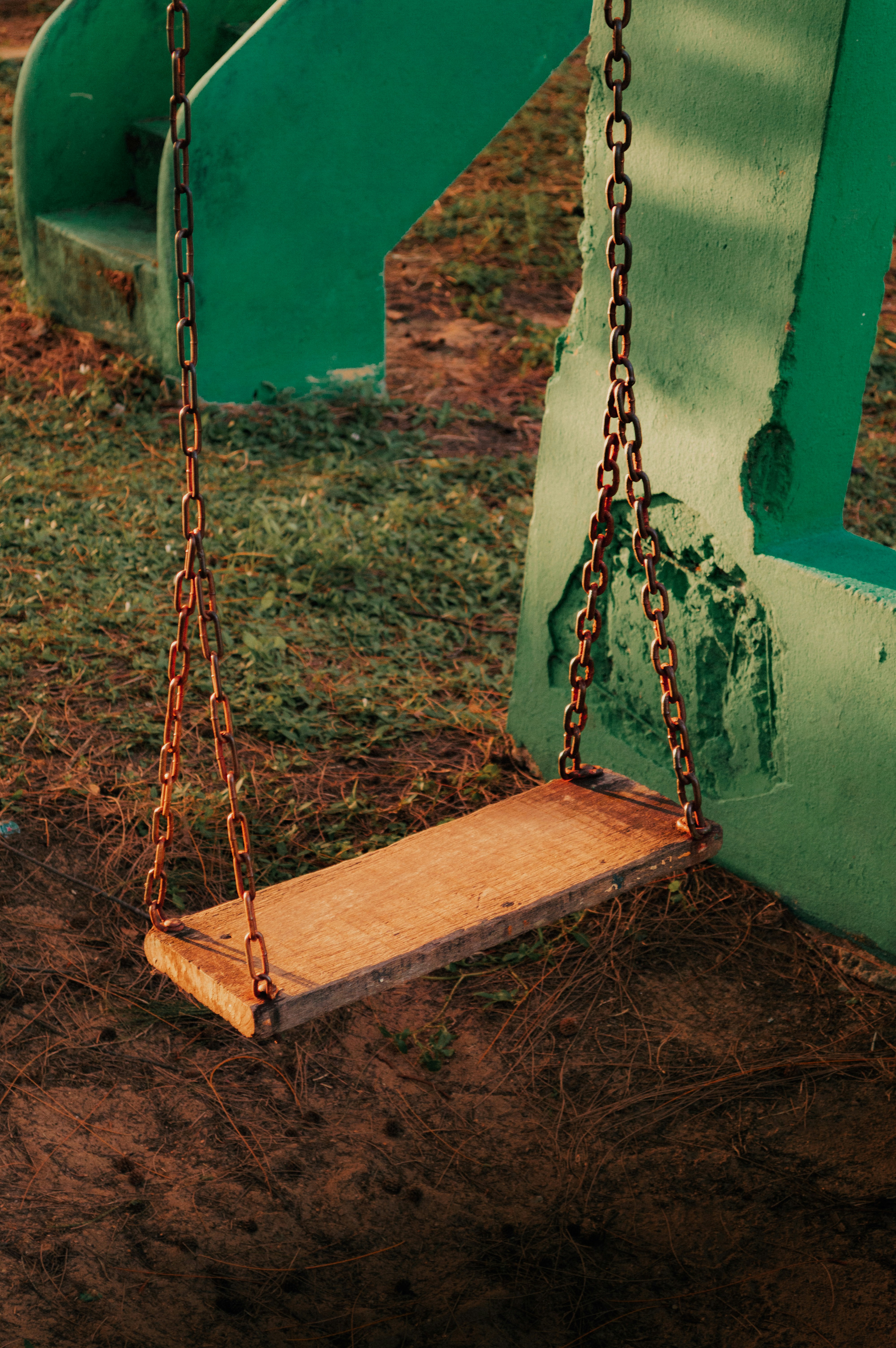 Green Playground: A Weathered Swing Suspended in Dappled Light