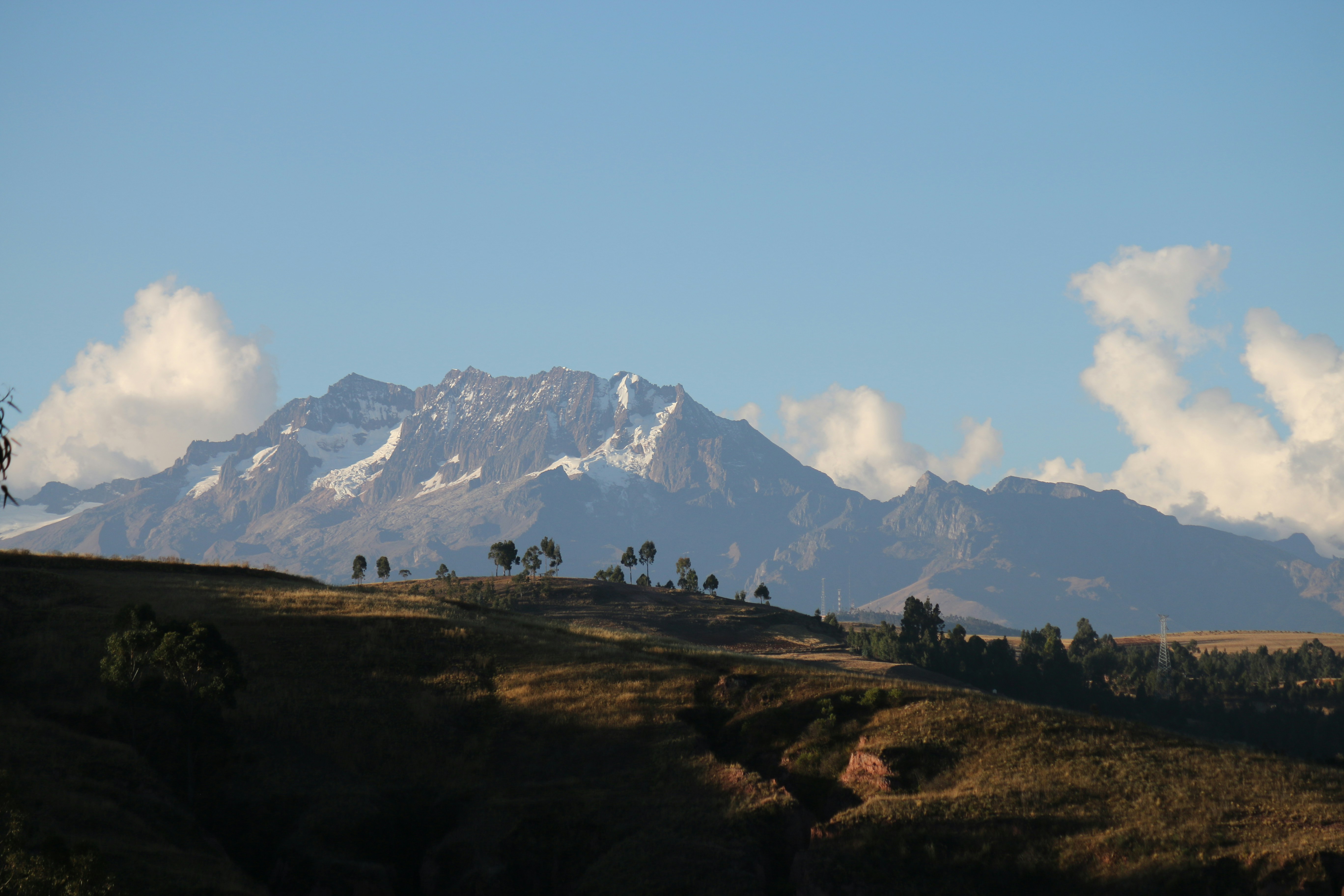 Snow-capped peak rising above rolling hills at golden hour