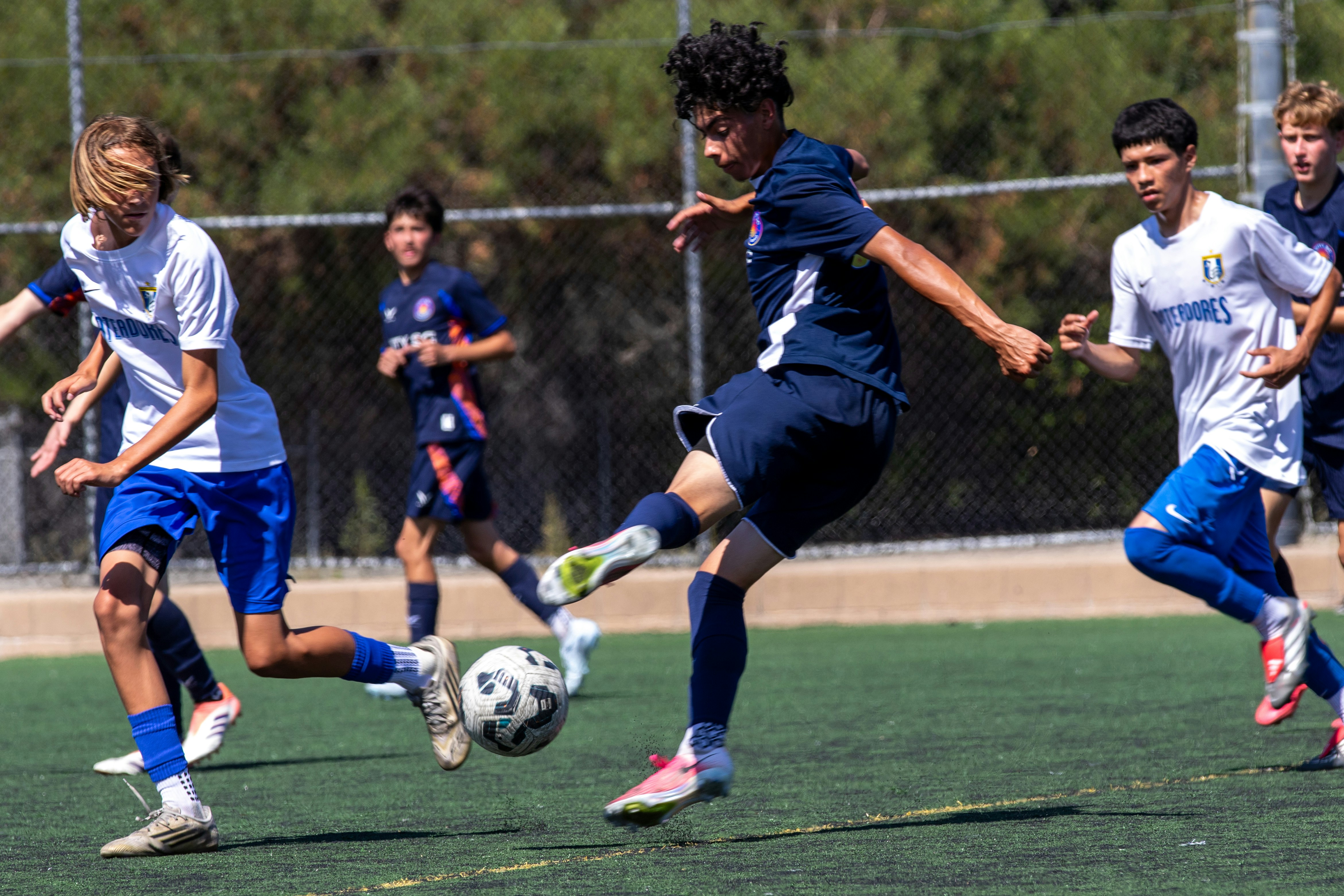 Midfield Momentum: A Player Strikes as Teammates Chase the Ball