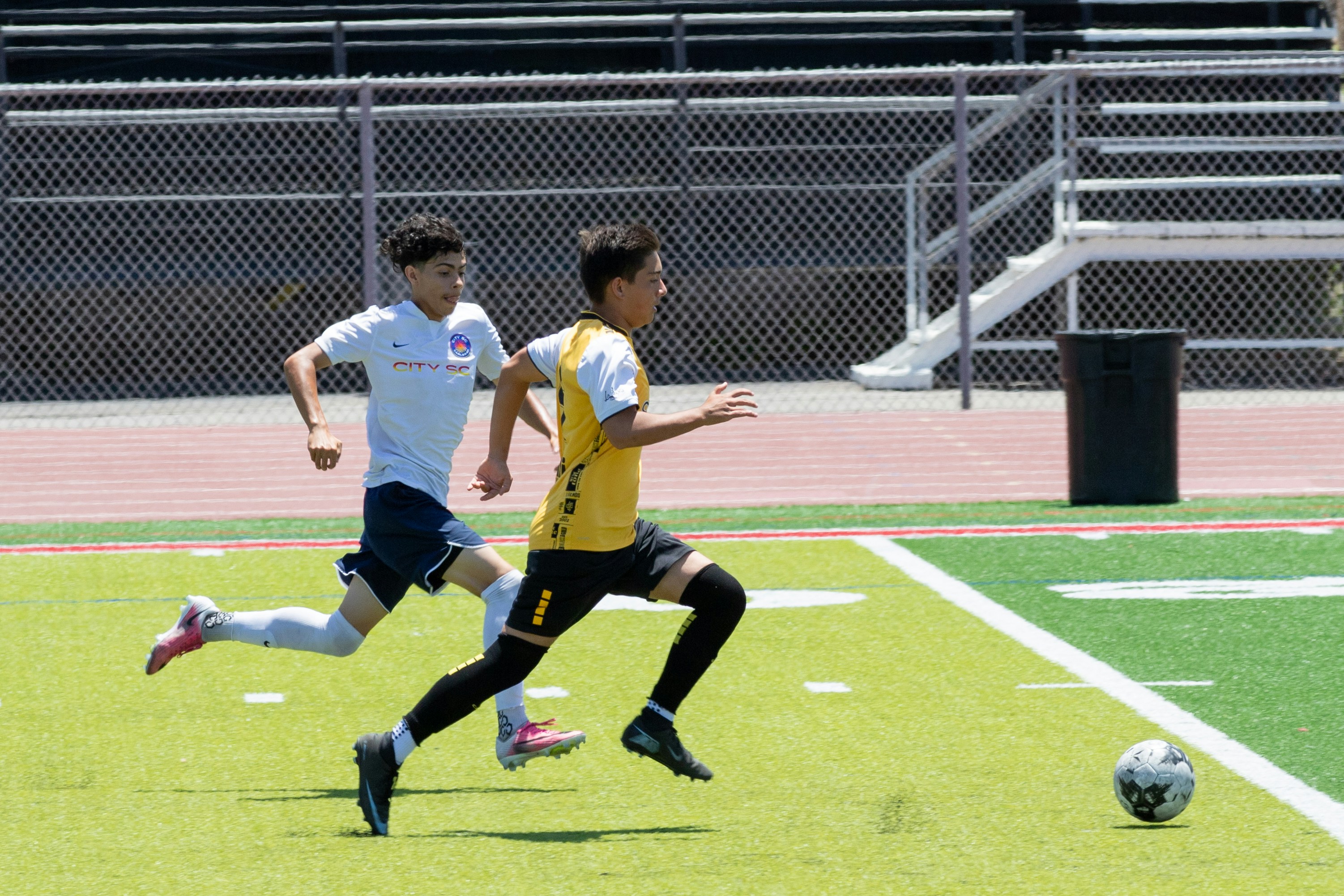 Two boys playing soccer on a green field.