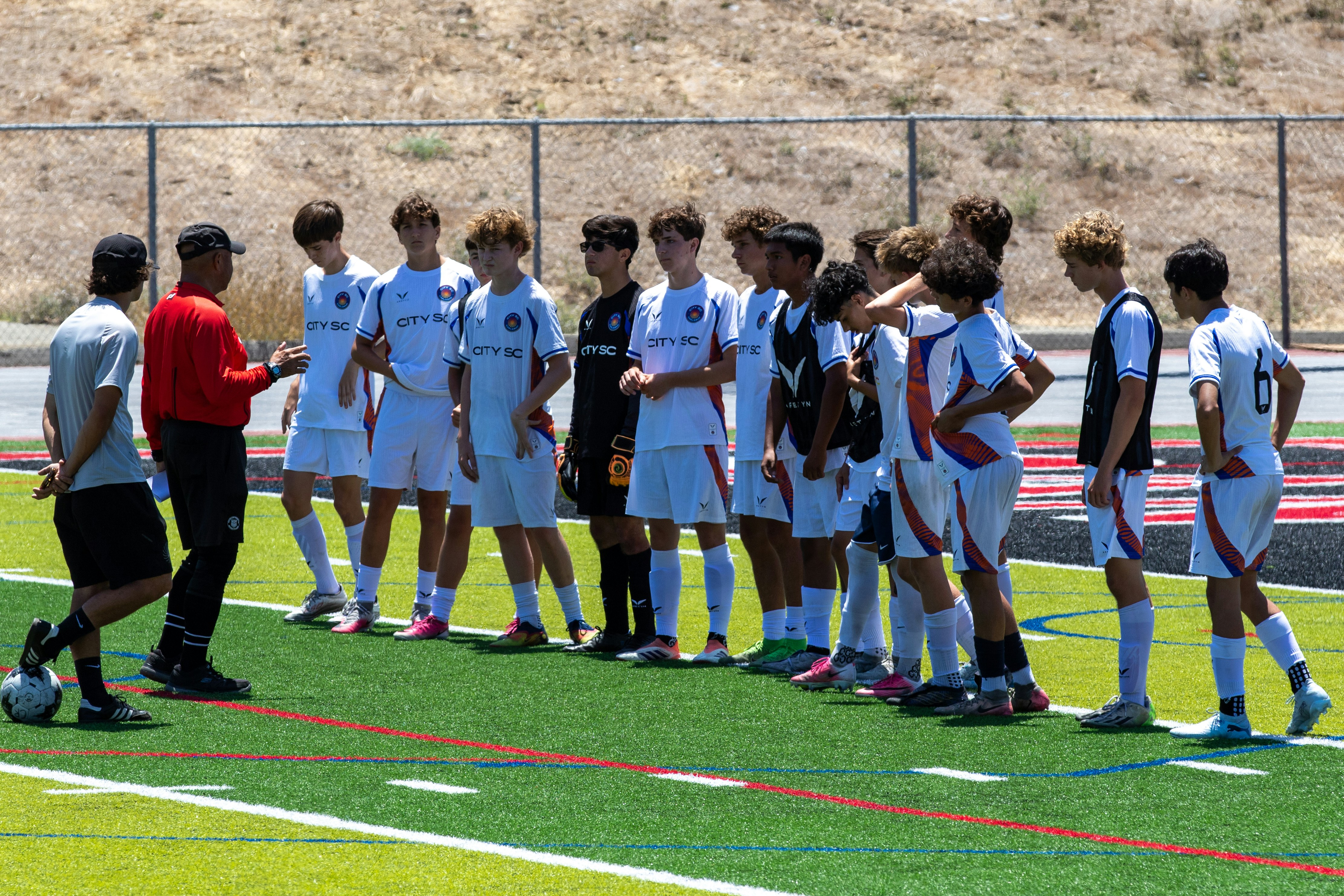 Team Huddle After the Whistle: White Jerseys Converge on the Coach