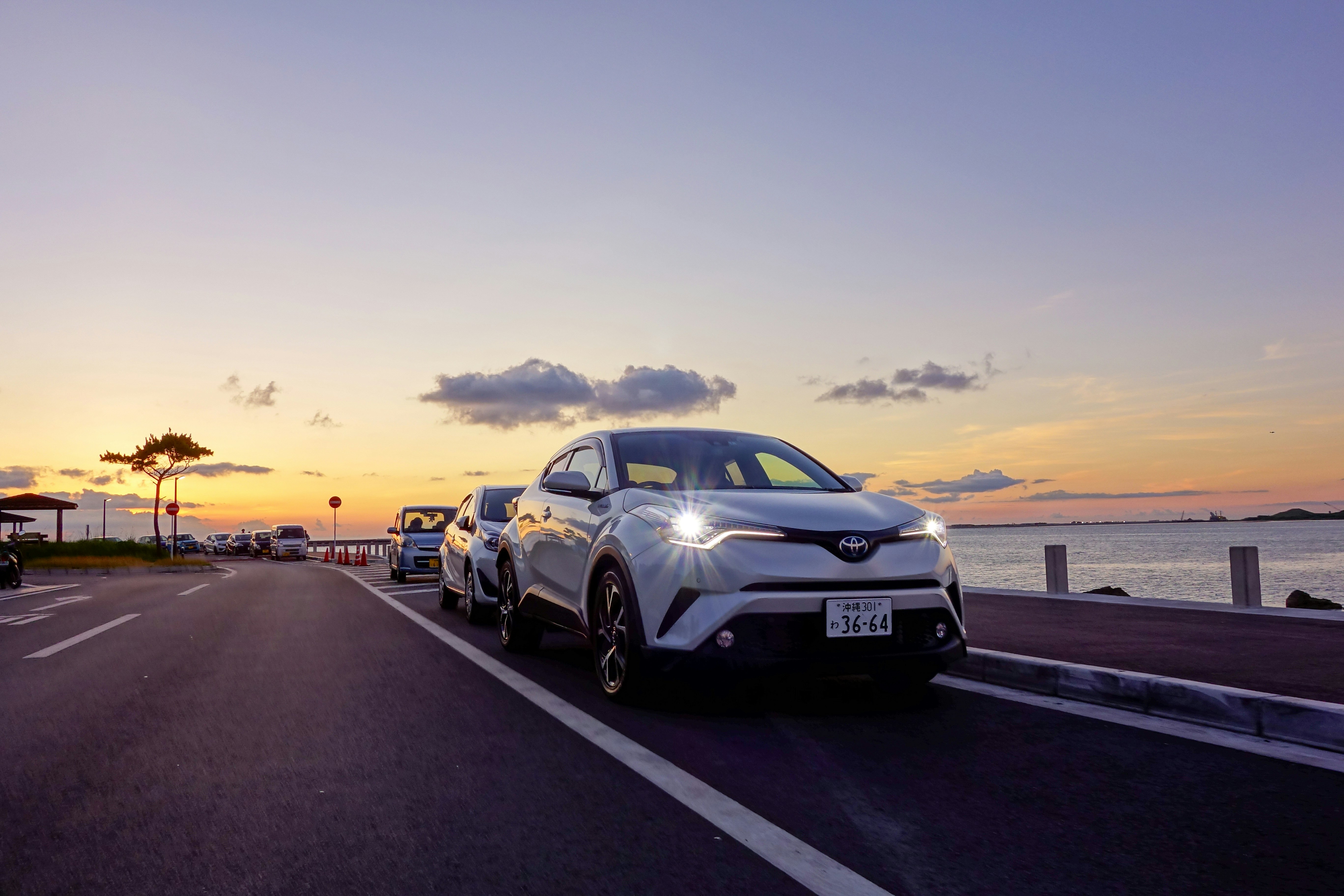 Sunlit lineup: a seaside road and the forward hatchback under dusk