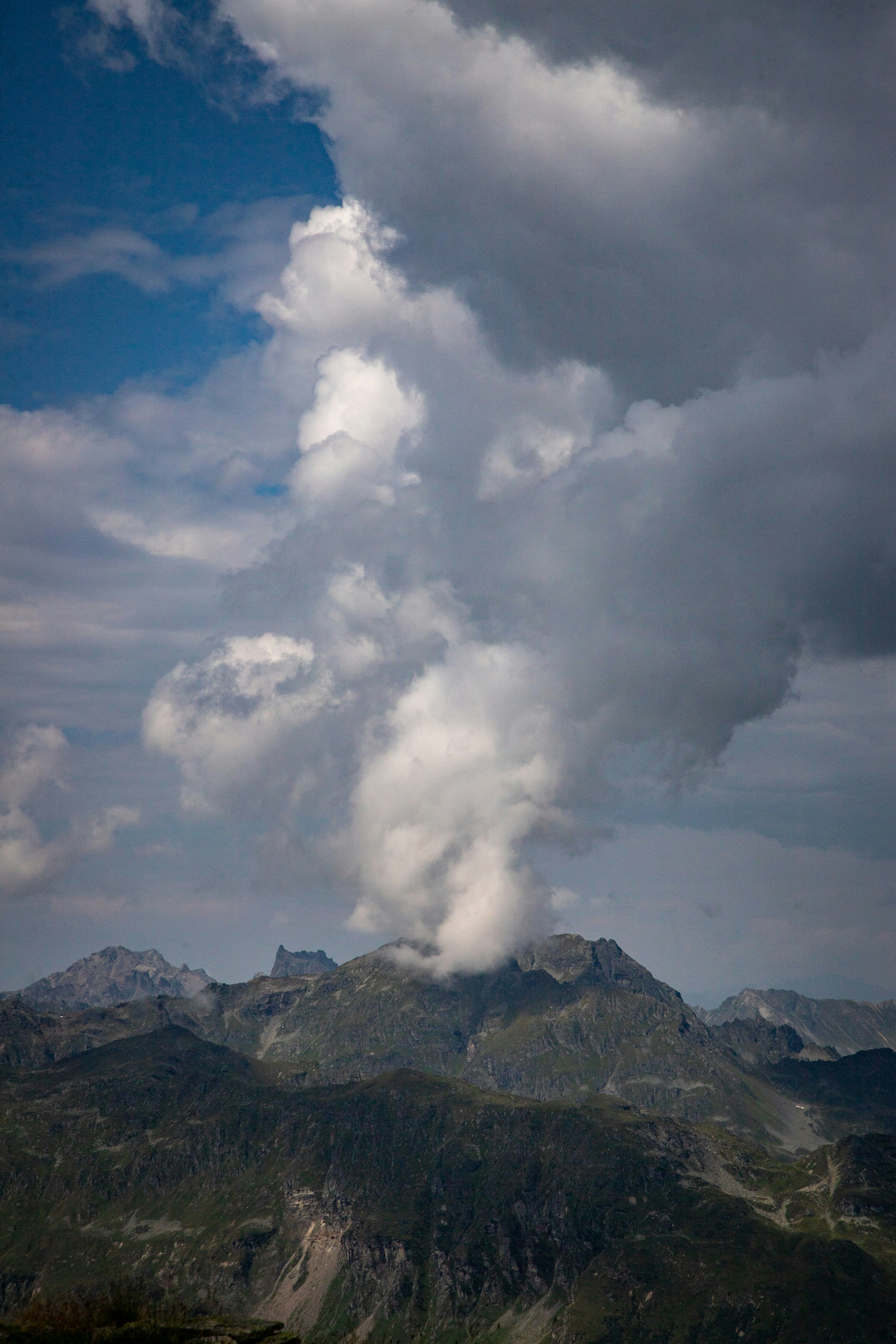 Steam Rising from Alpine Summit: A Cloud Veil over Rugged Peaks
