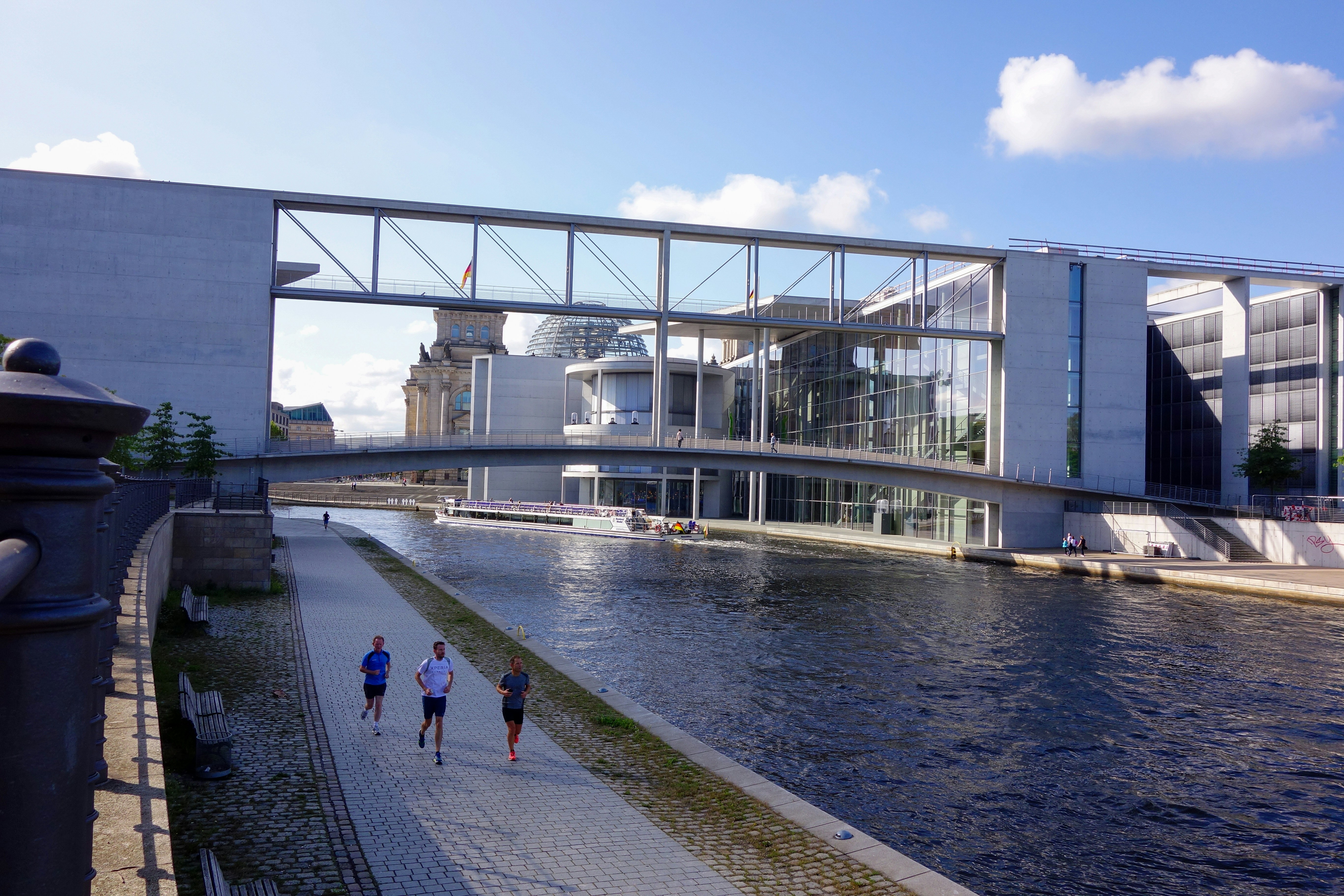 Riverside Footpath Framed by Modern Architecture and a Glass Link Suspension
