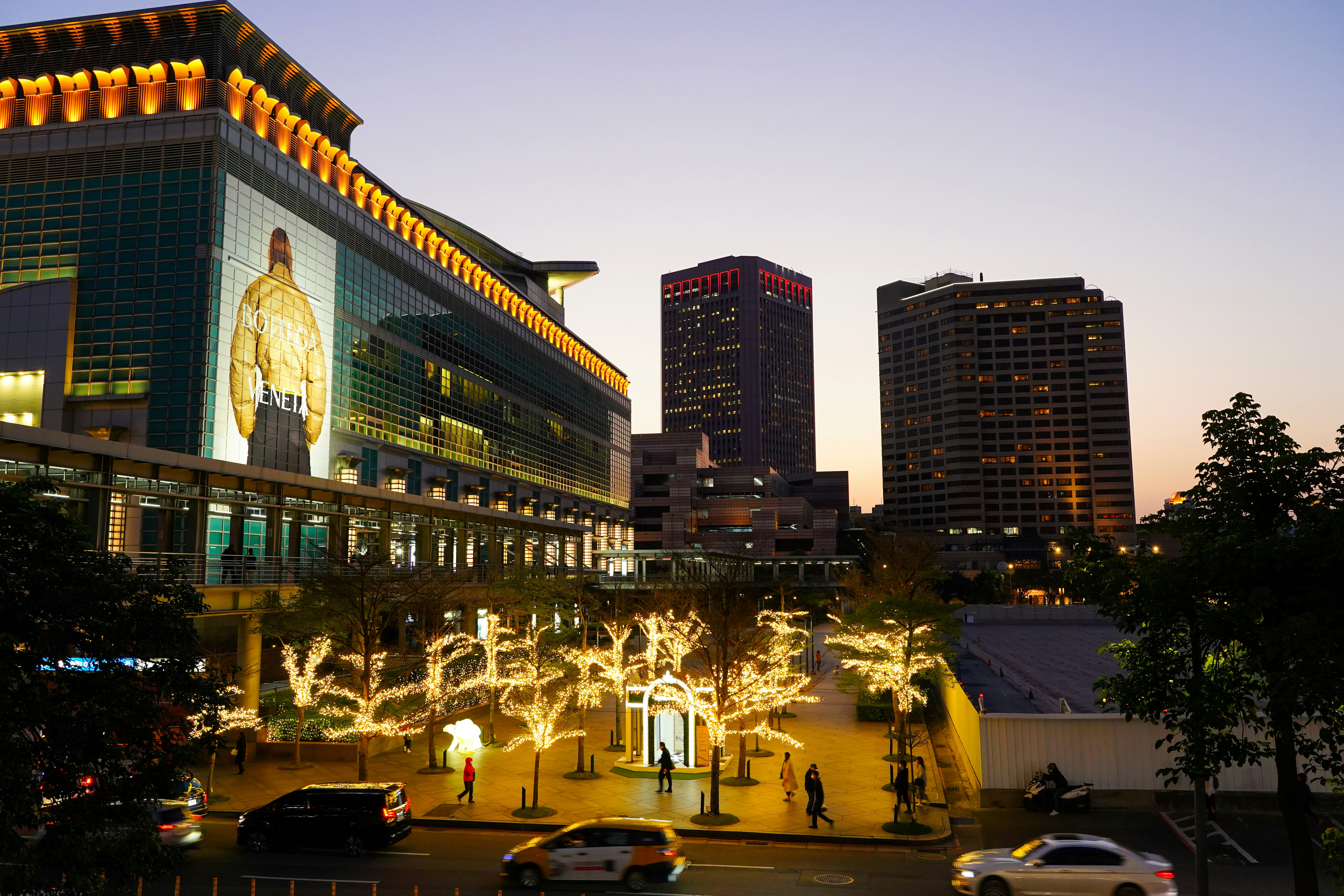 Illuminated business district at dusk with a glass-front mall