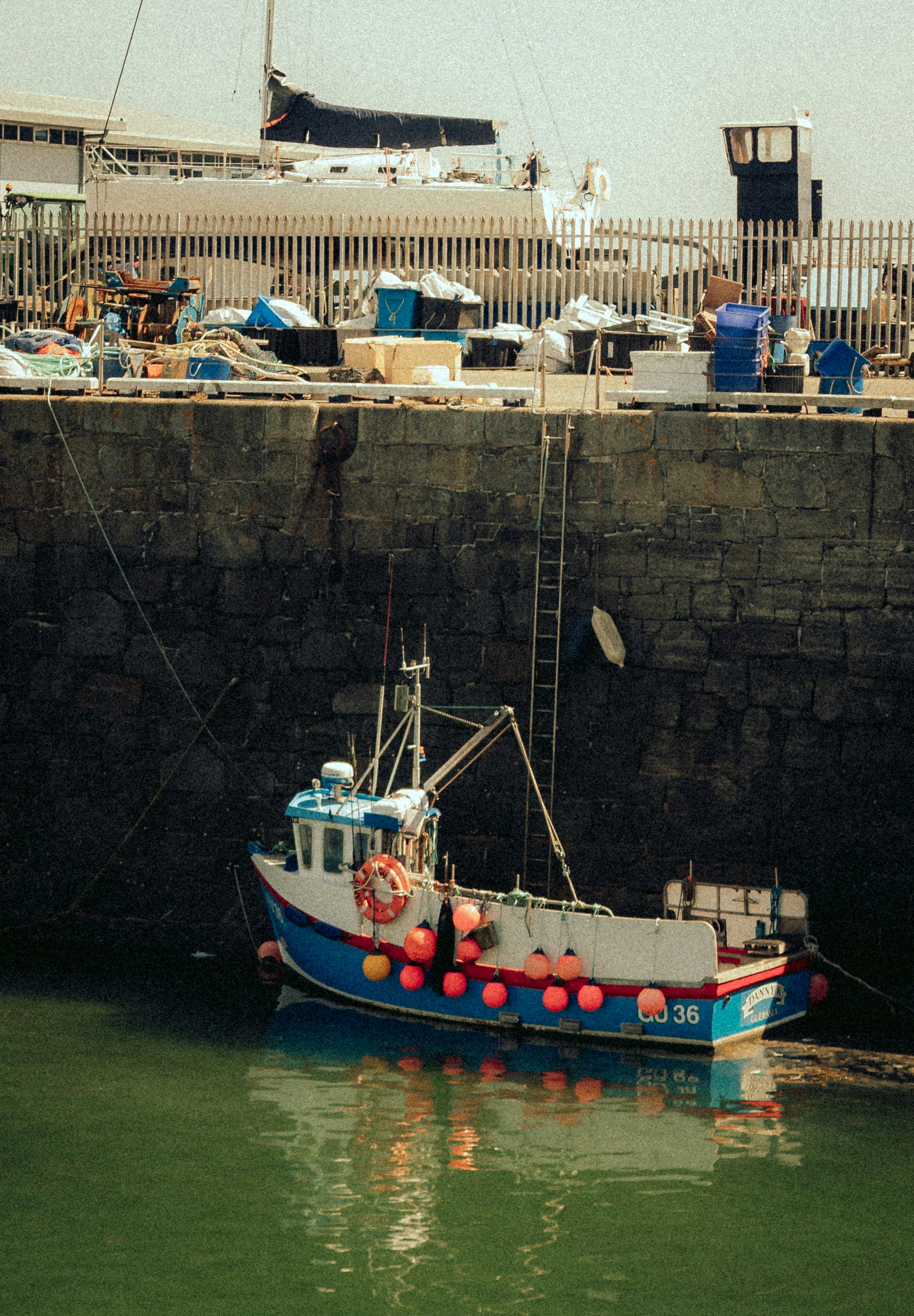 Blue-Tipped Buoy at Docks: A Lone Fishing Vessel in Calm Green Water