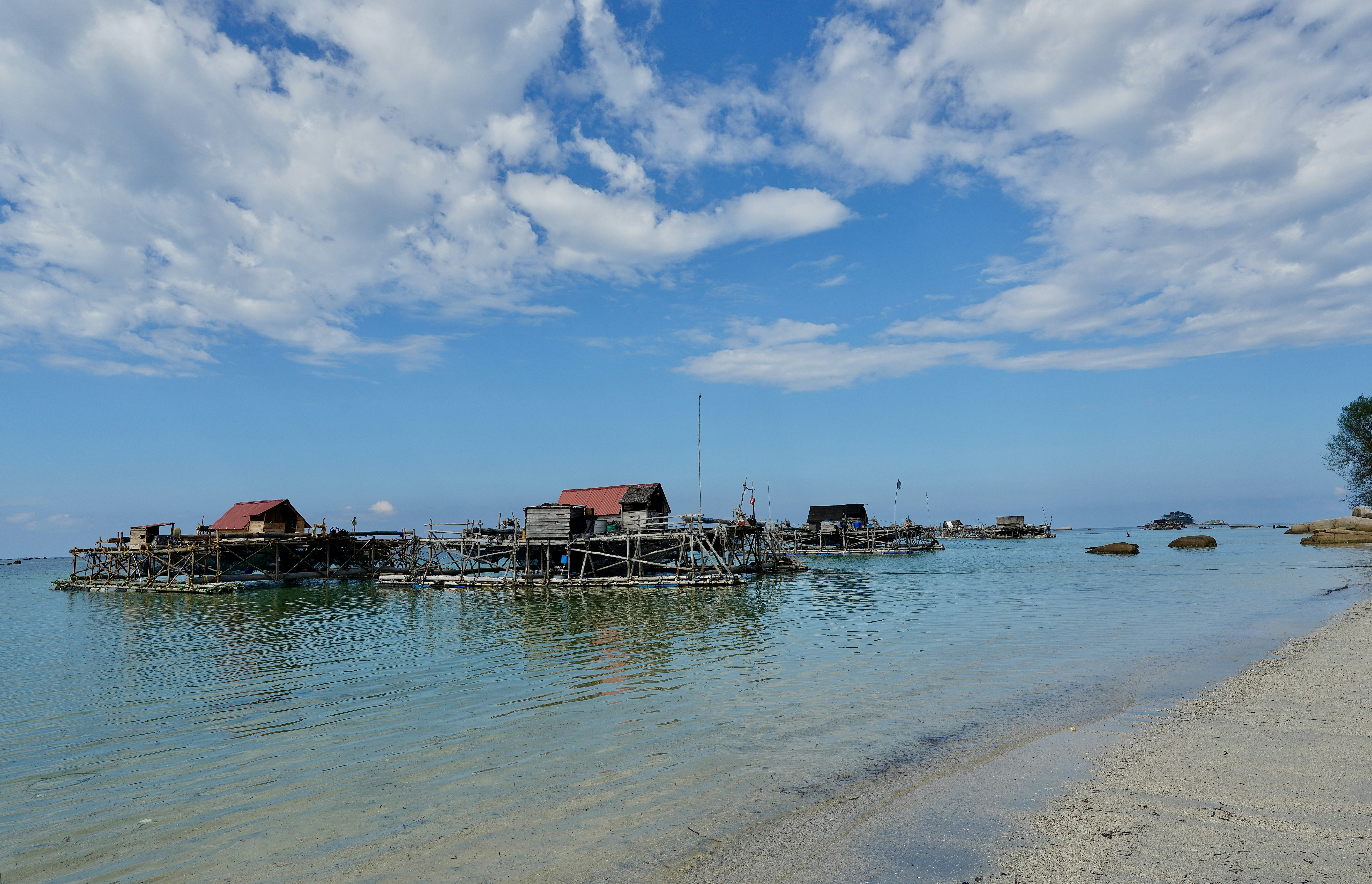 Stilted huts over turquoise shallow waters under a bright coastal sky