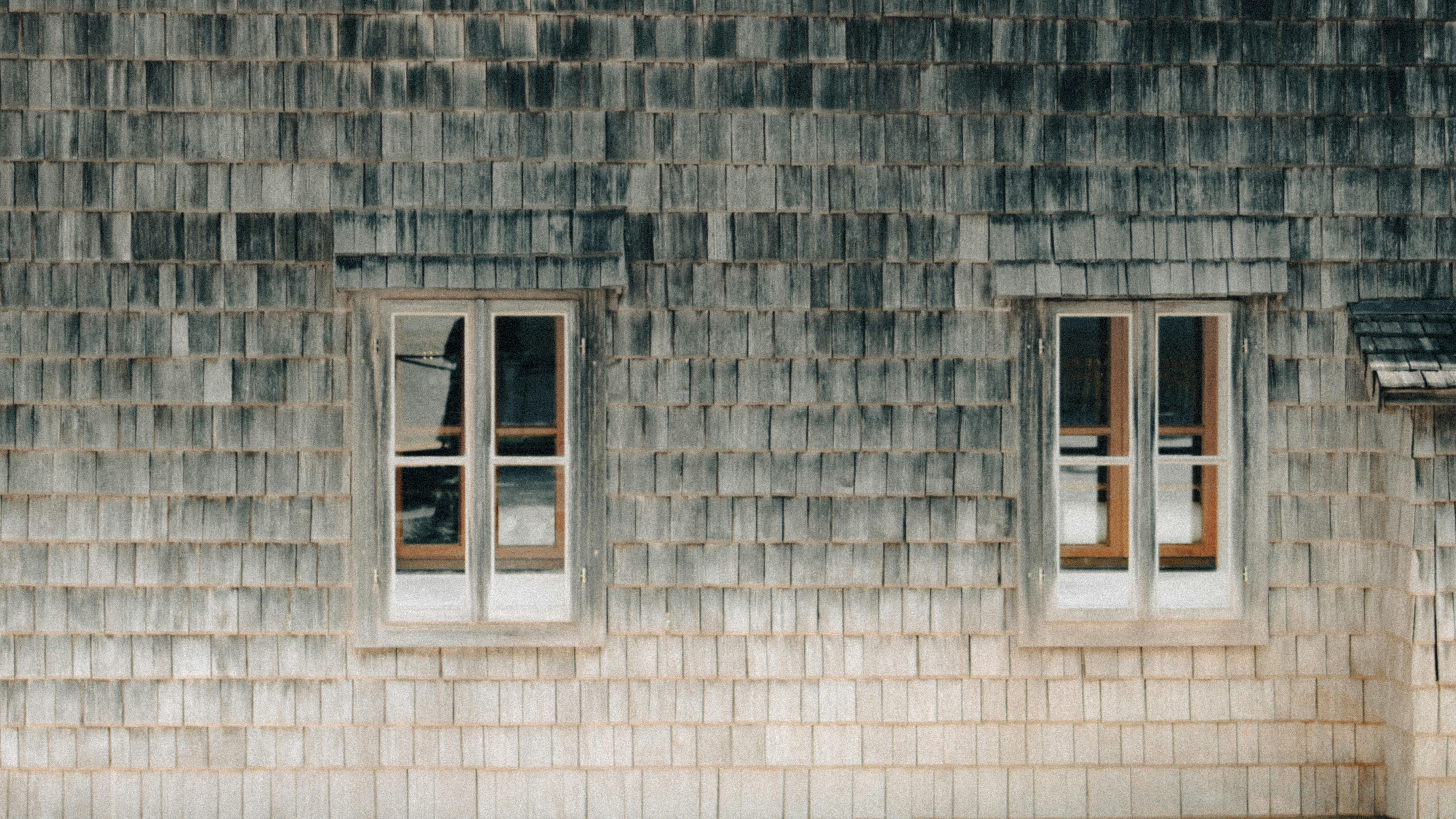 Weathered shingles and twin windows: a quiet facade in light