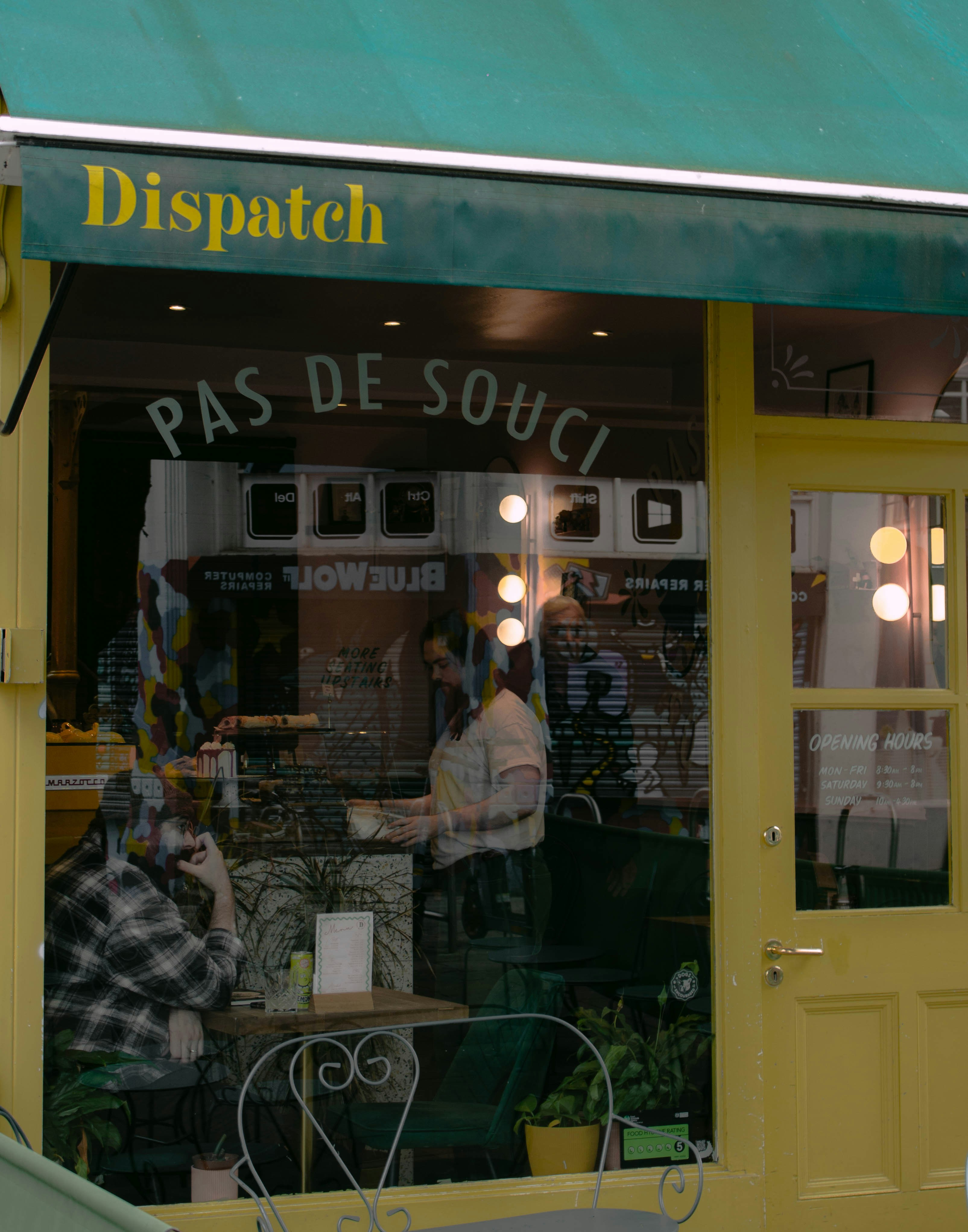 Dispatch Café Window: Warm Yellow Door Framed by Green Awning