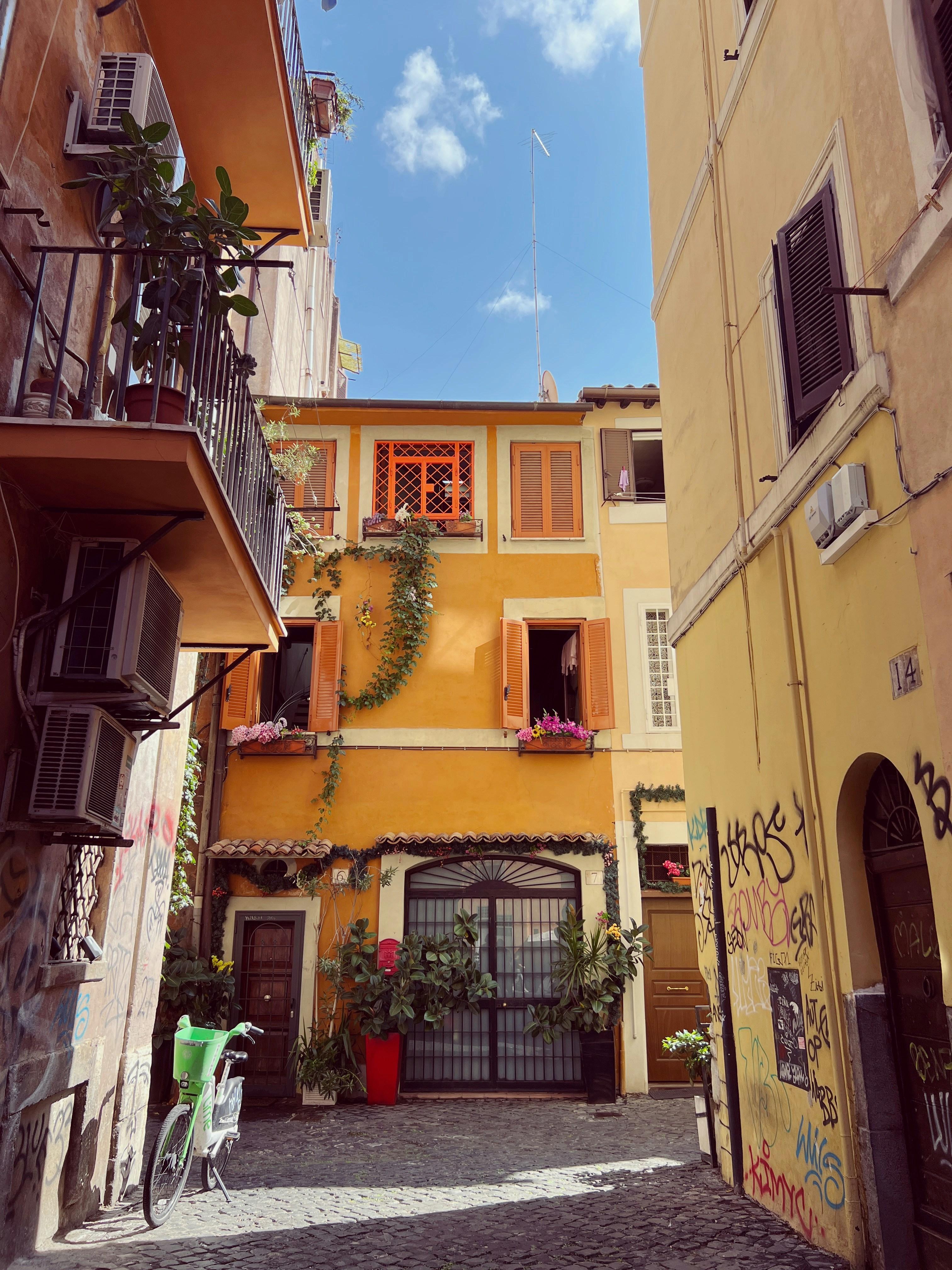 Golden Lane: Sunlit Facade and flowering balcony in a narrow Italian alley