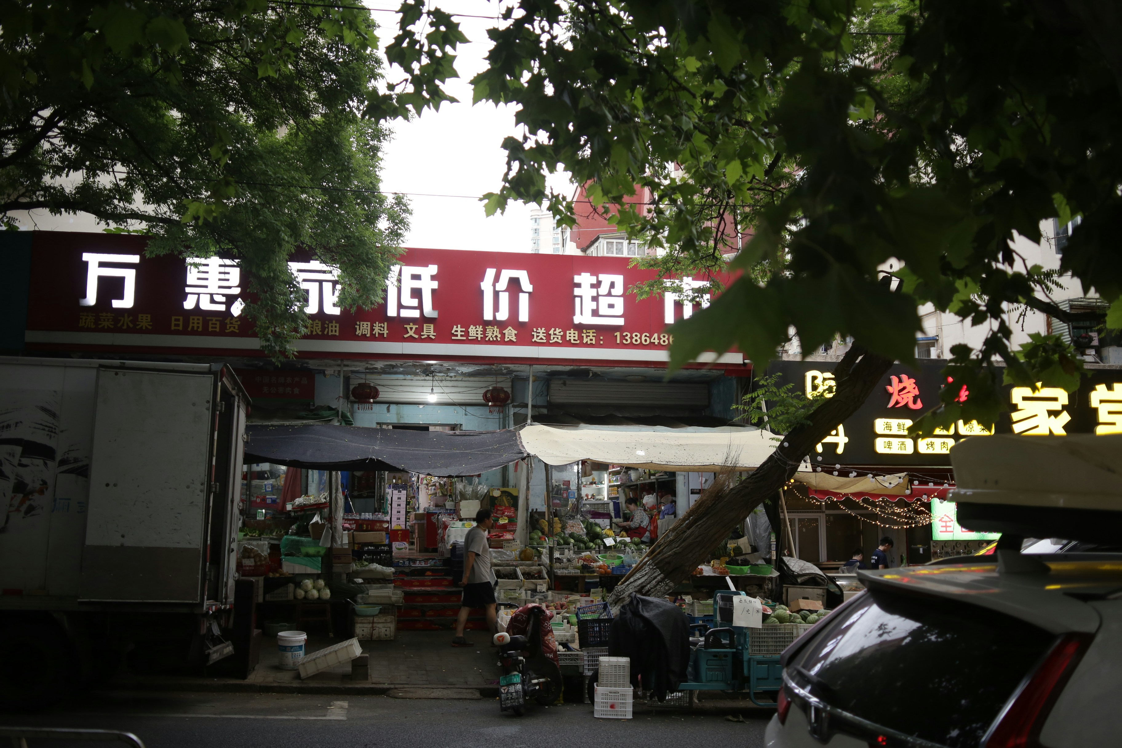 Overhead Green Canopy Over a Bustling Market Front