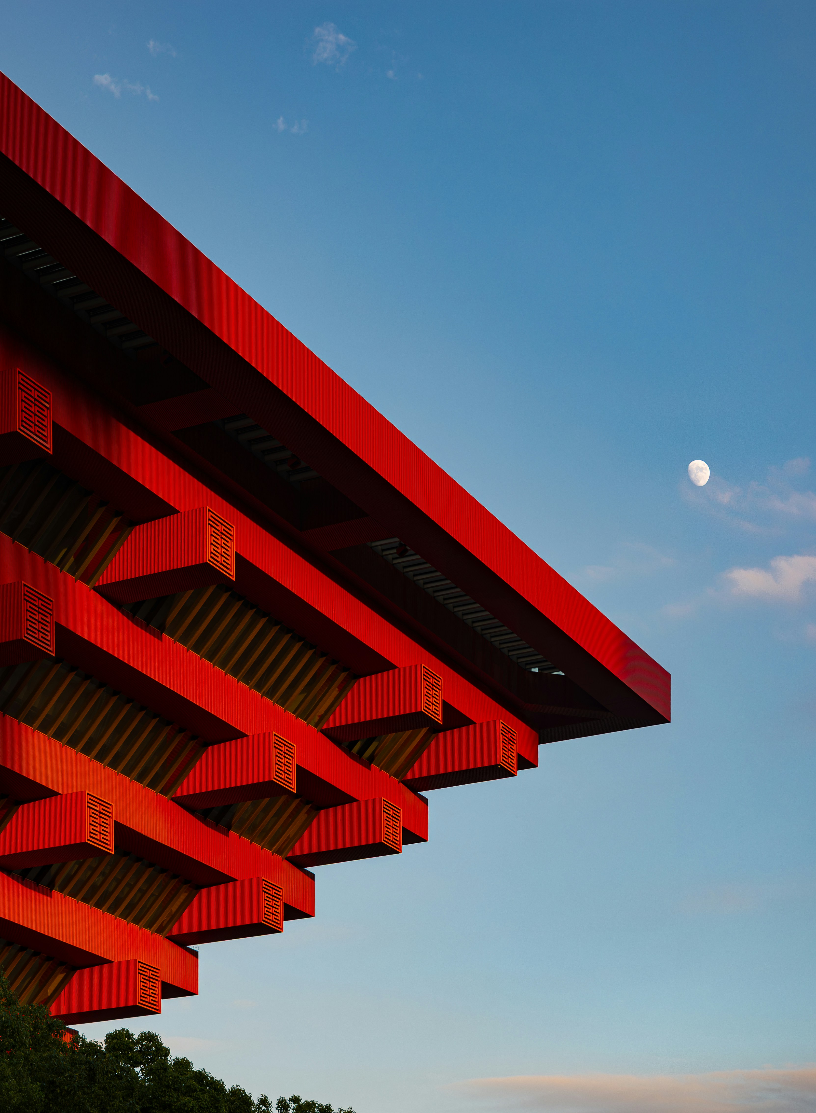 Red Cantilevered Roof Framing Under a Vivid Sky with a Moon