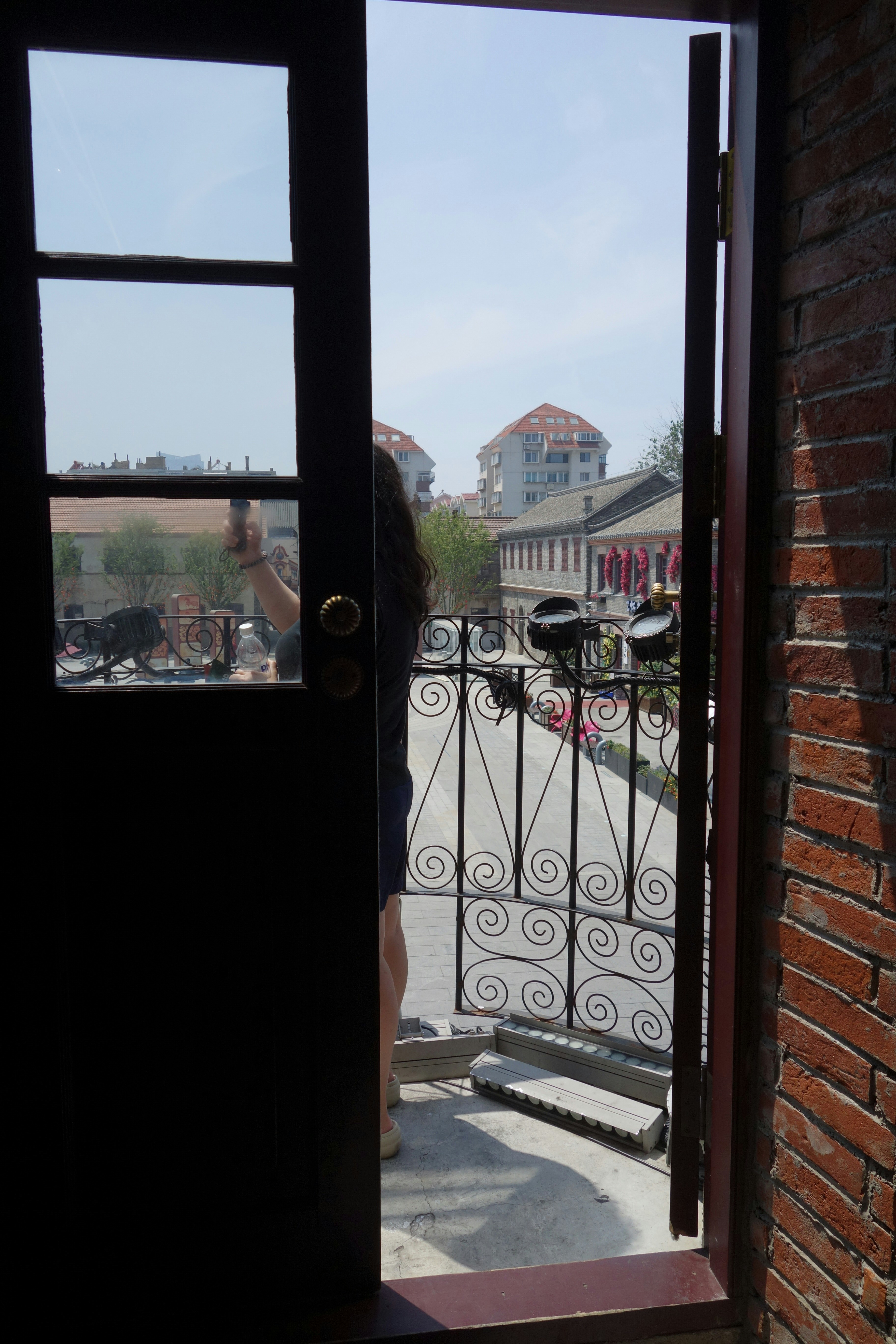 Doorway to the Terrace: A Quiet Balcony Frame Beyond Brick Walls