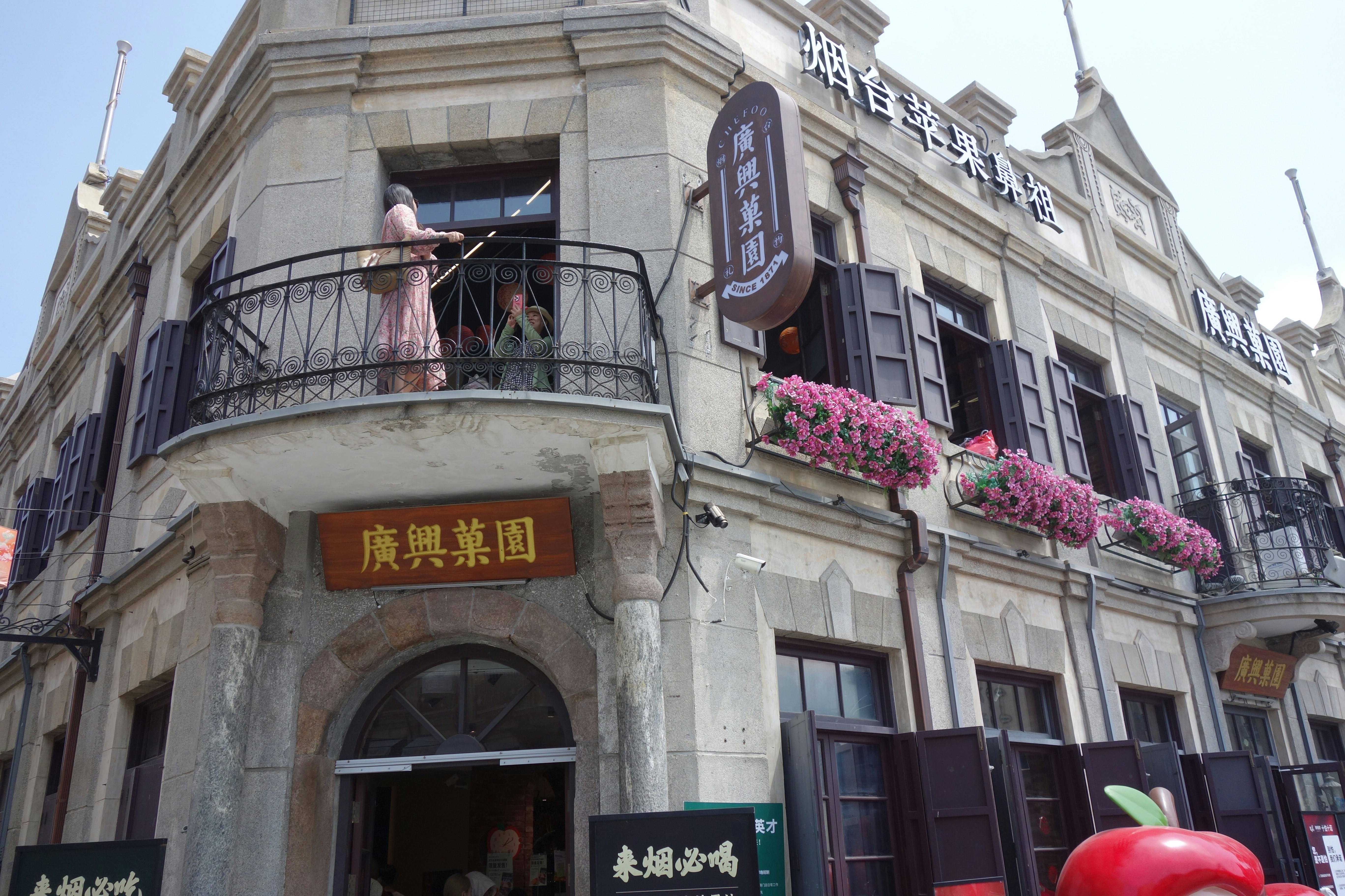 Heritage Corner: Balcony Figures Overlooking a Stone Facade
