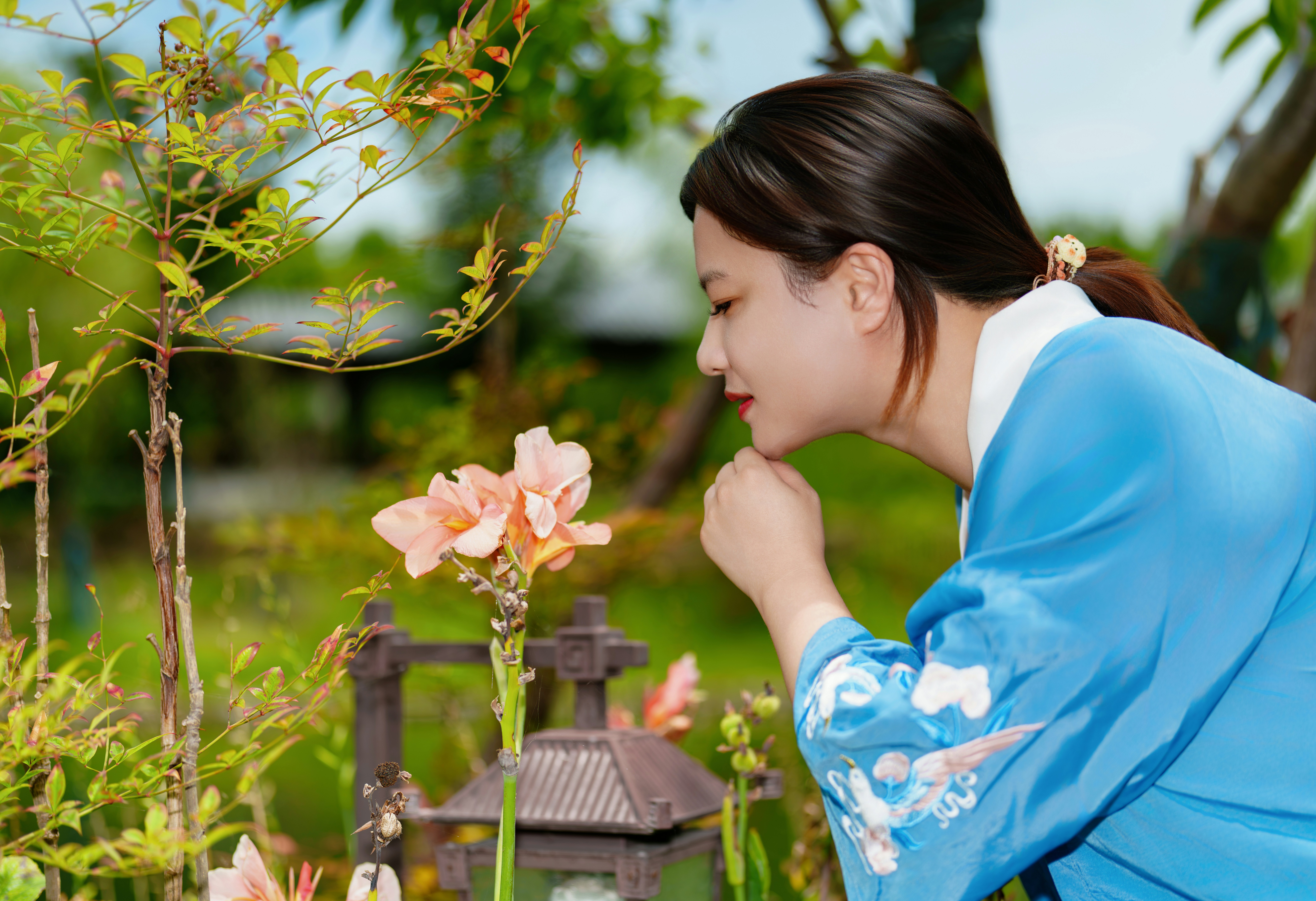 A Quiet Moment: A Woman in a Blue Kimono Examines a Blossoming Garden