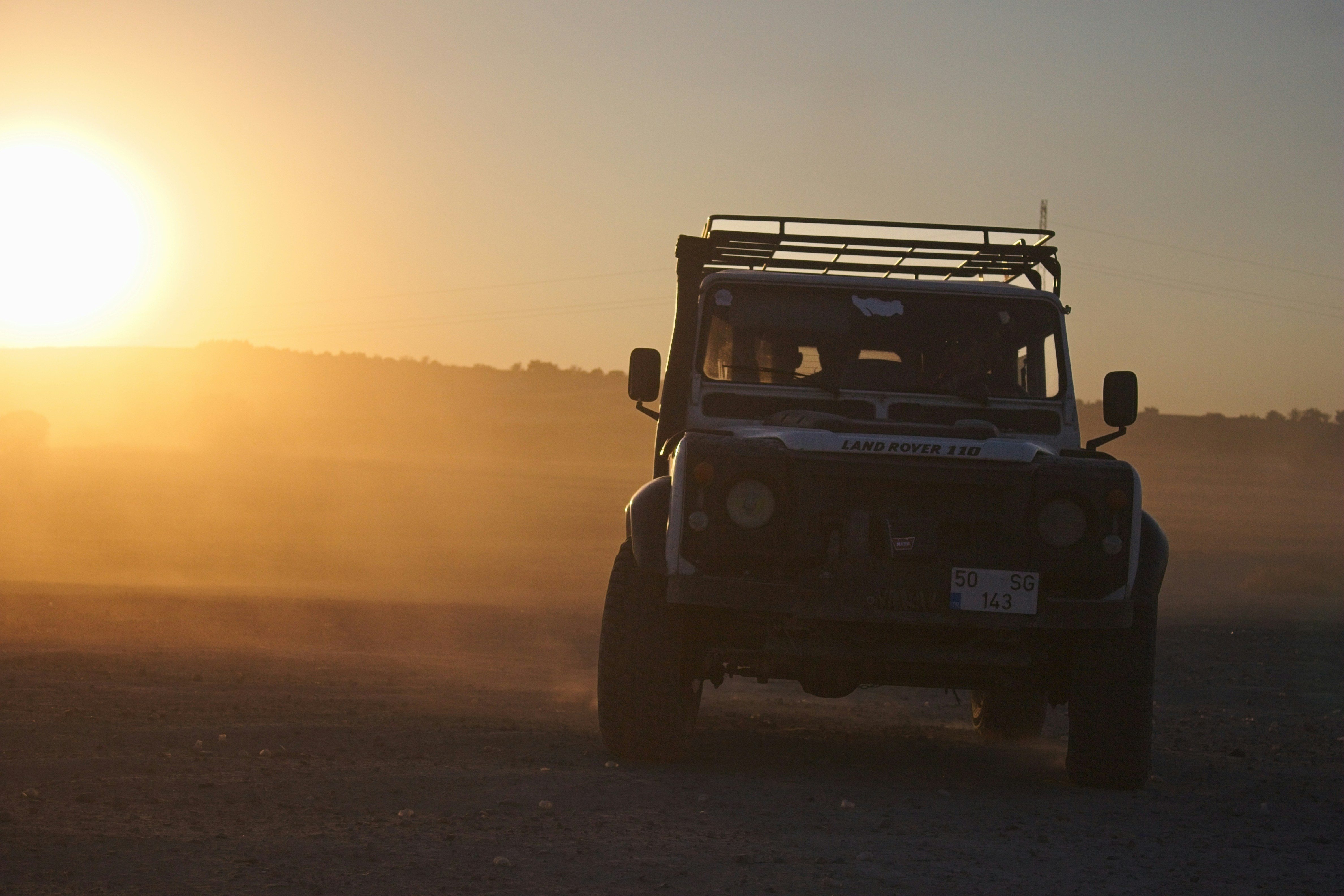Sunlit Dune Runner: A silhouetted Jeep in a desert dusk