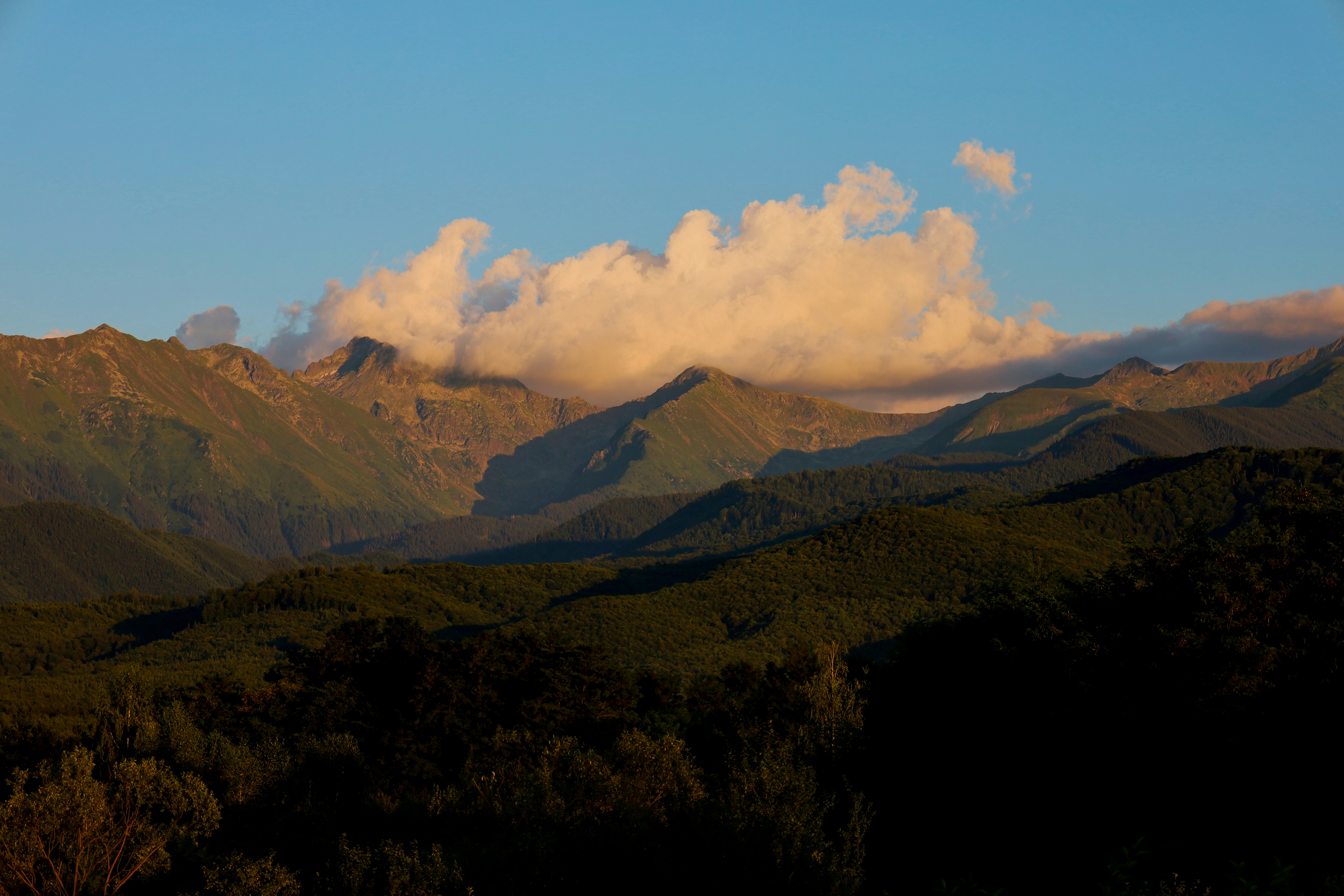 Golden Summit: Clouds Drift Over Mountain Crest at Dusk