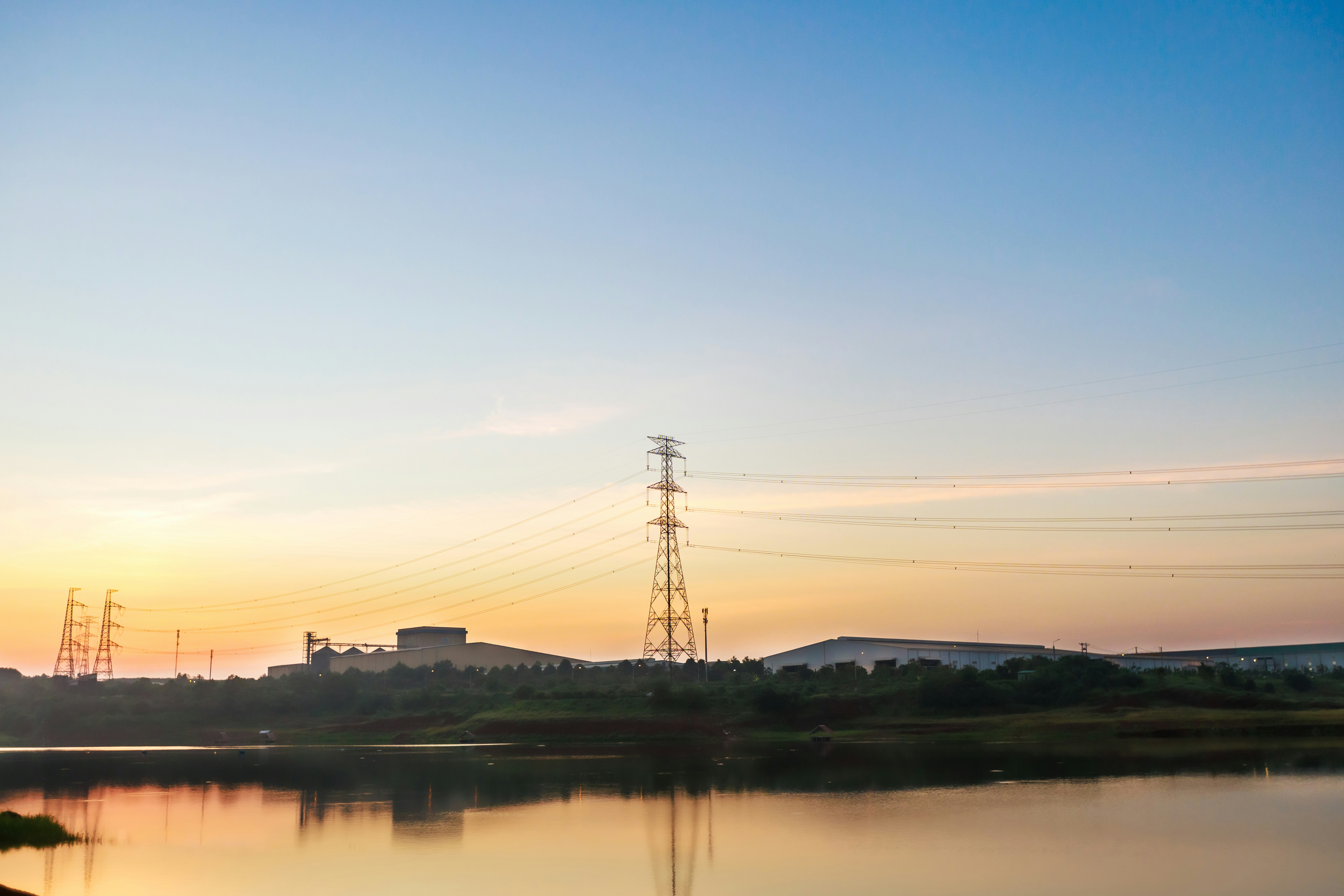 Low-lying industrial silhouette at sunset over a glassy river