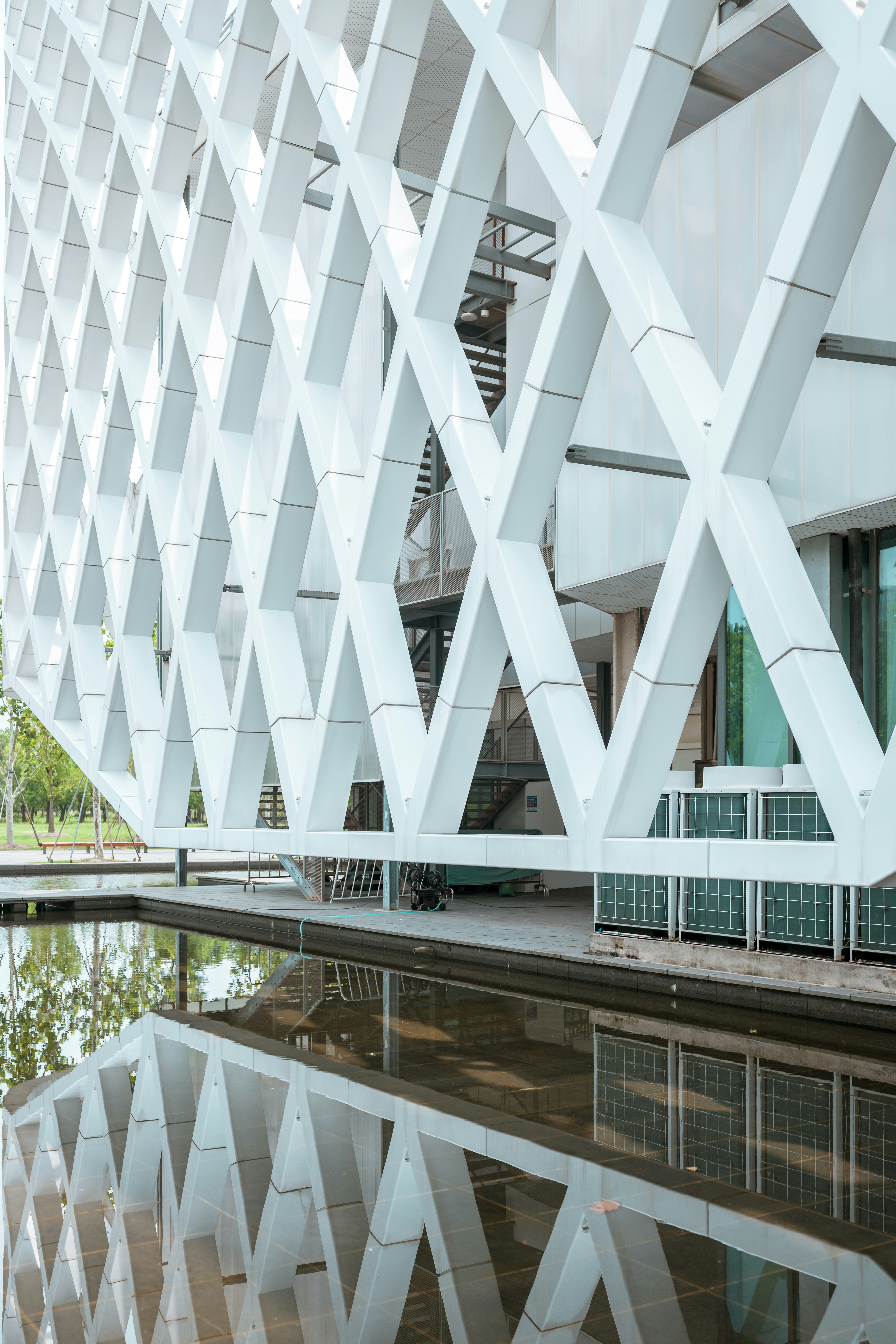 Architectural detail of a diagonal lattice building with its reflection visible in a calm canal.