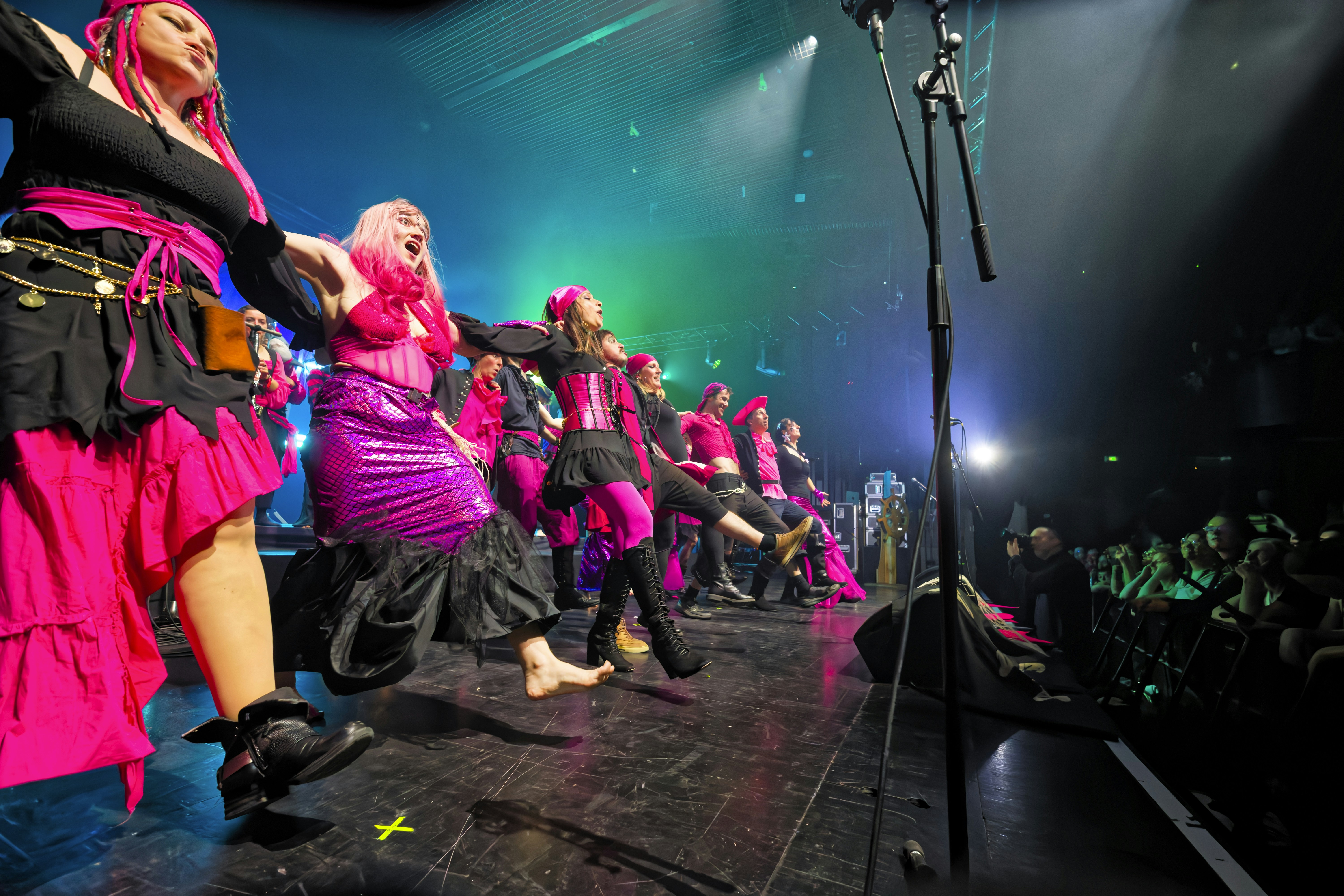 Vivid Convergence: A Dizzying Line of Dancers in Neon Stagelight
