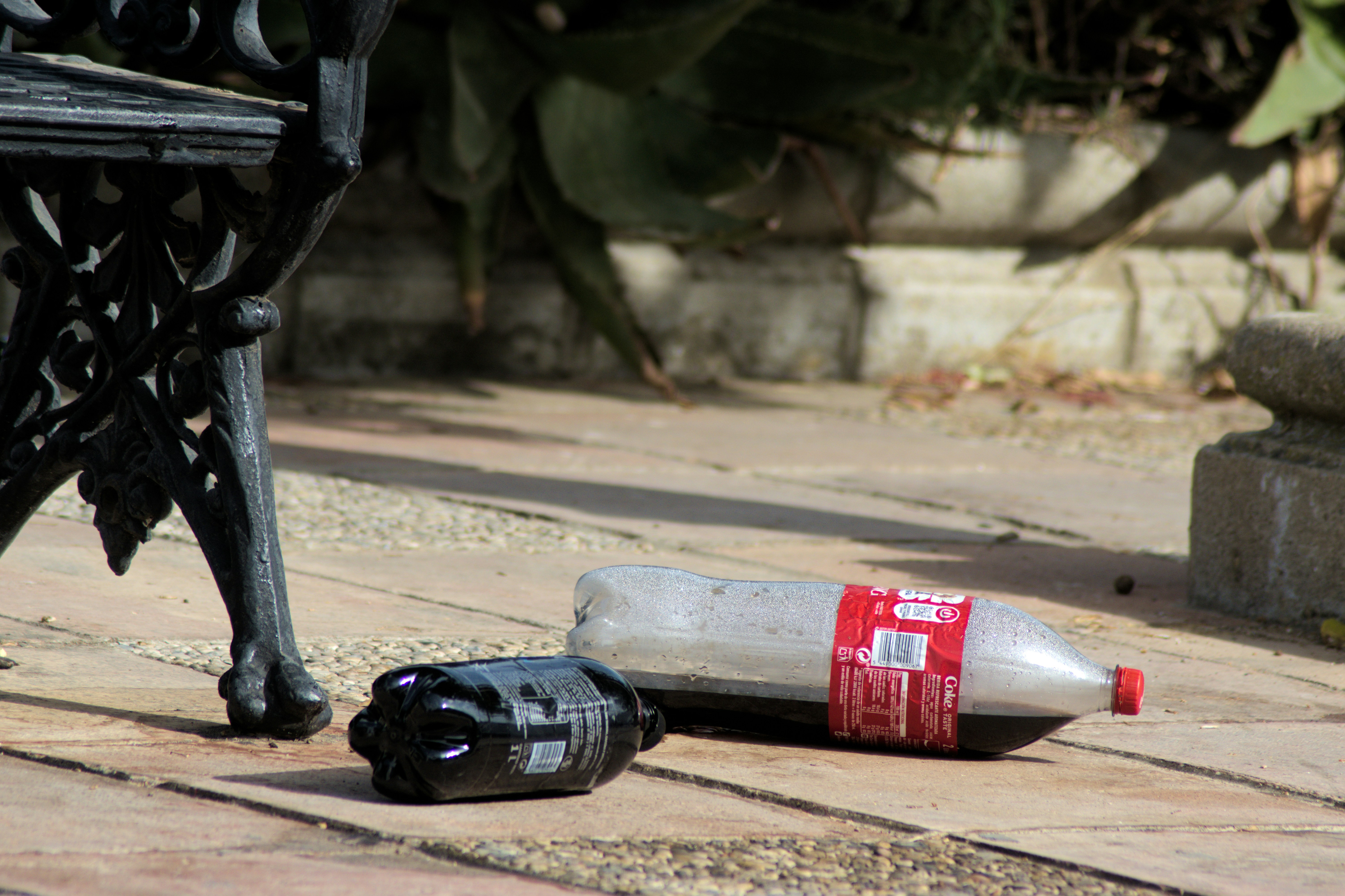 Discarded soda bottles cast shadow on sunlit stone path