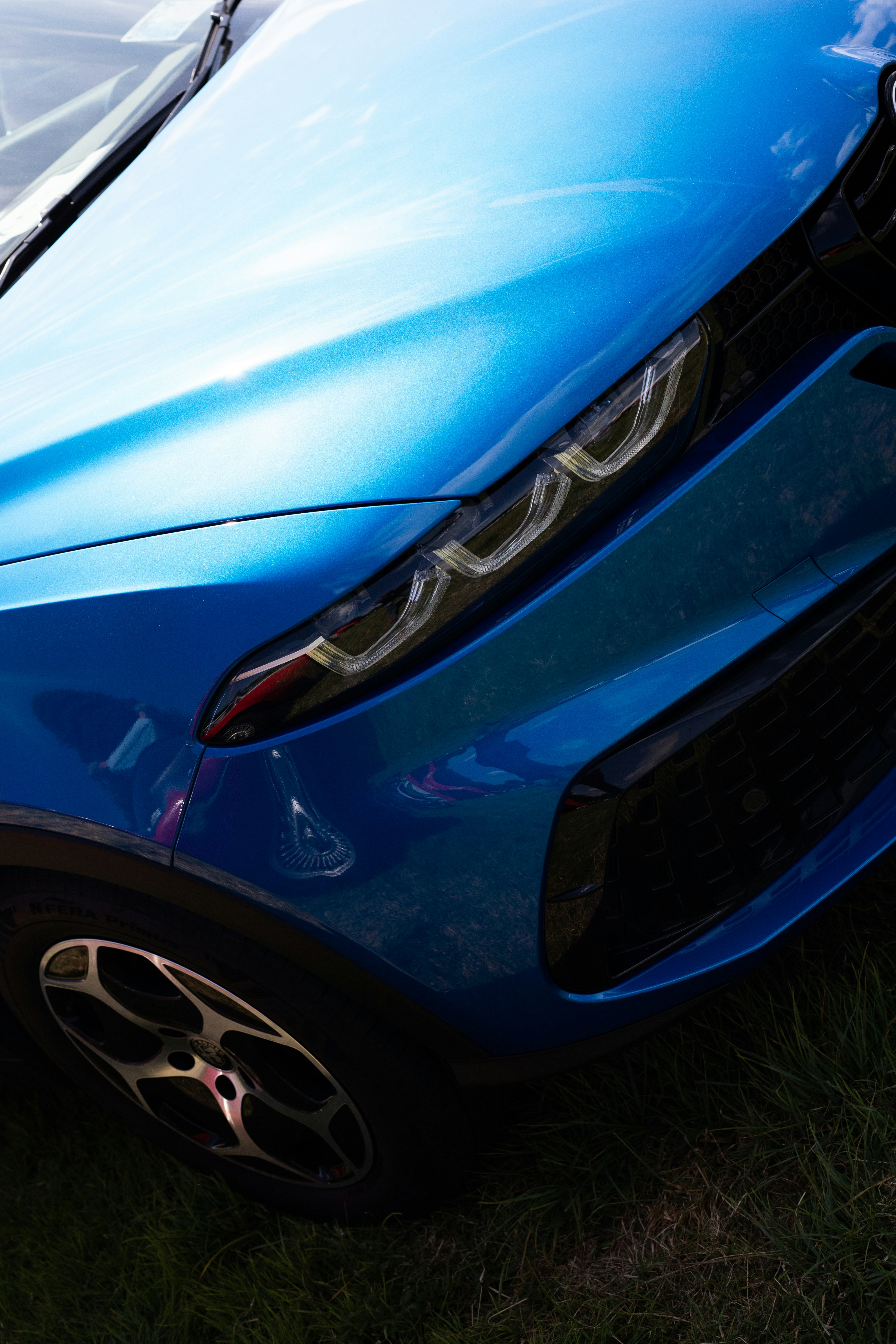 Blue Velocity: Close-Up of a Curved Car Nose and Headlight Detail