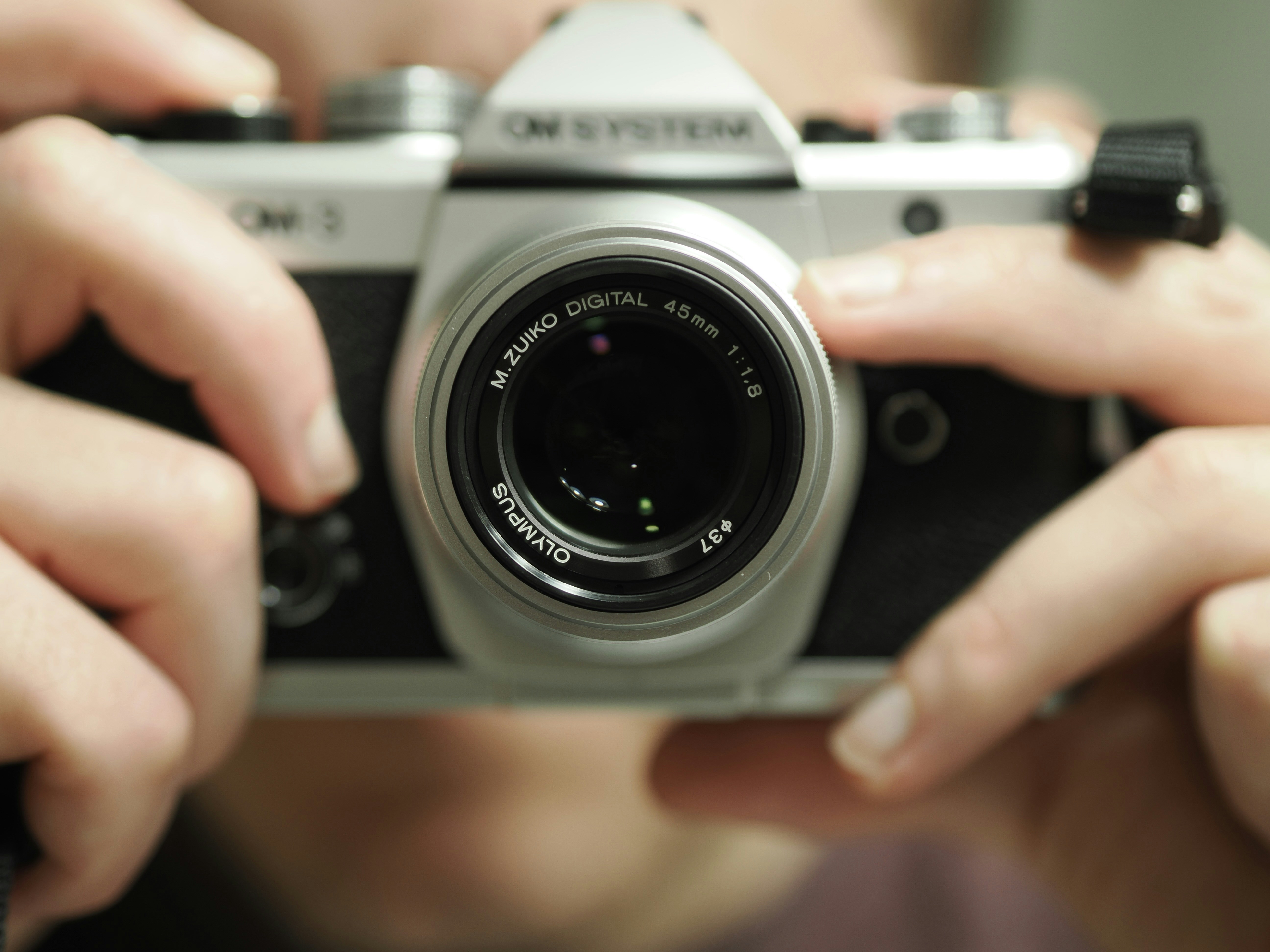 Center of Focus: A Vintage Olympus Lens Peering Through a Hands-On Camera