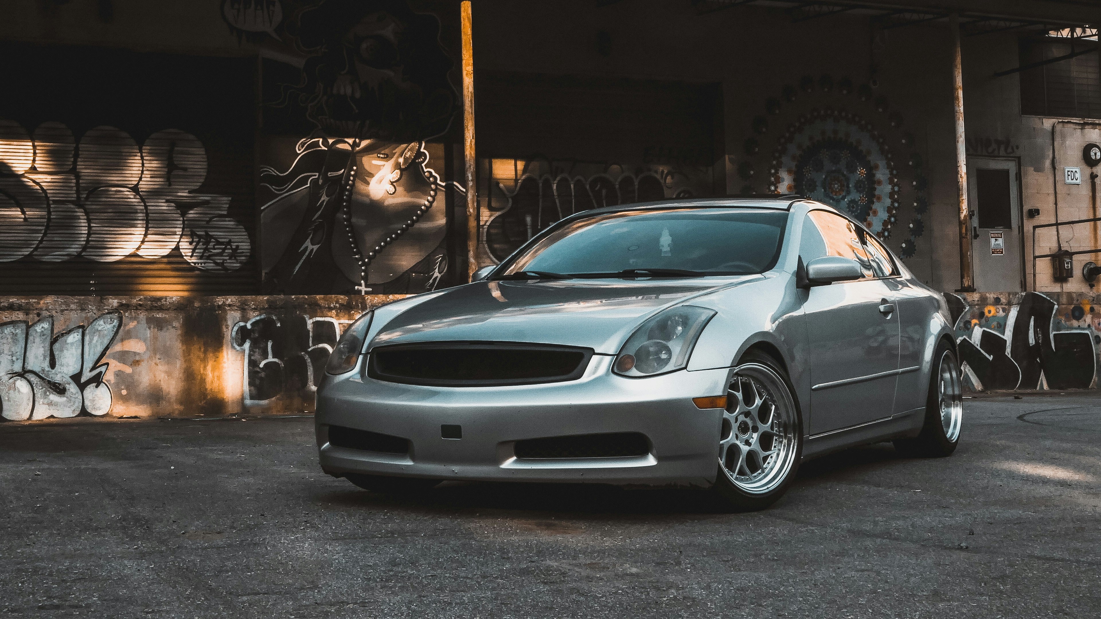 Low-Slung Silhouette: Silver Sedan in Urban Graffiti Spotlight