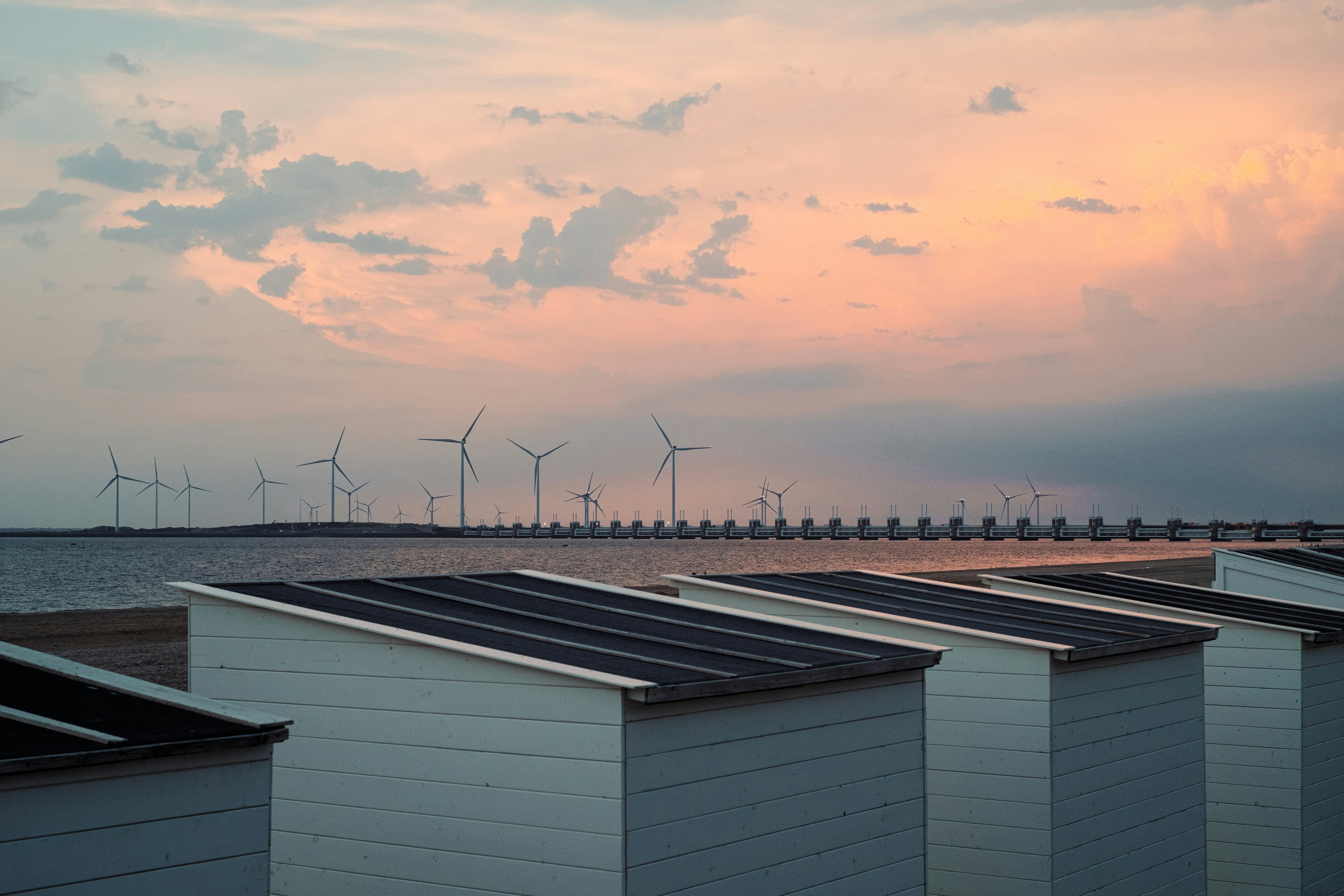 Coastal Rooftops Facing a Distant Wind Farm at Dusk