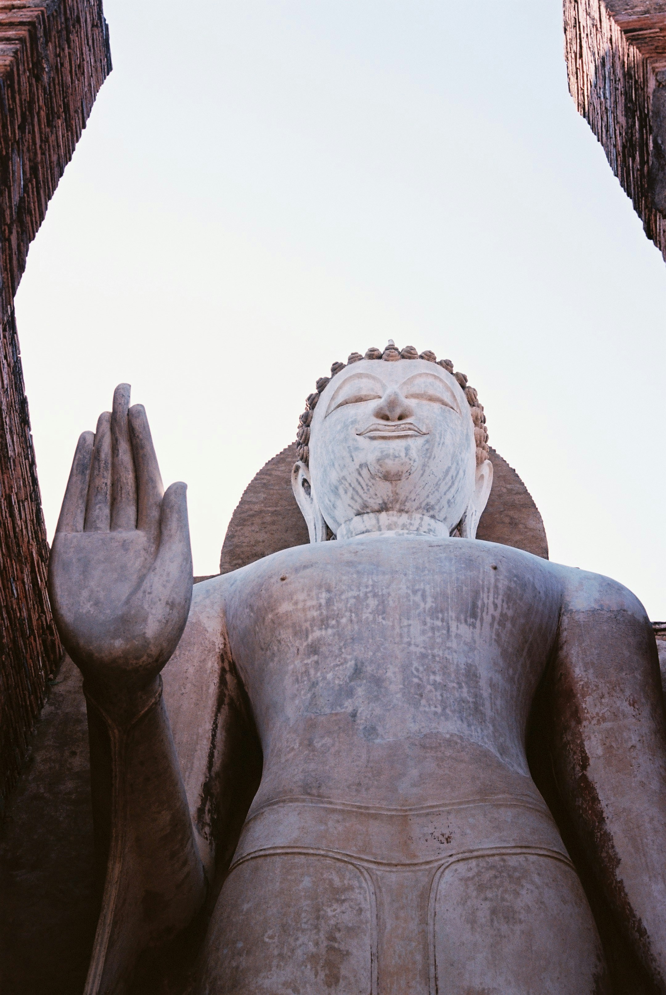 Massive Buddha Sentinel: Upward Gaze Between Ancient Walls