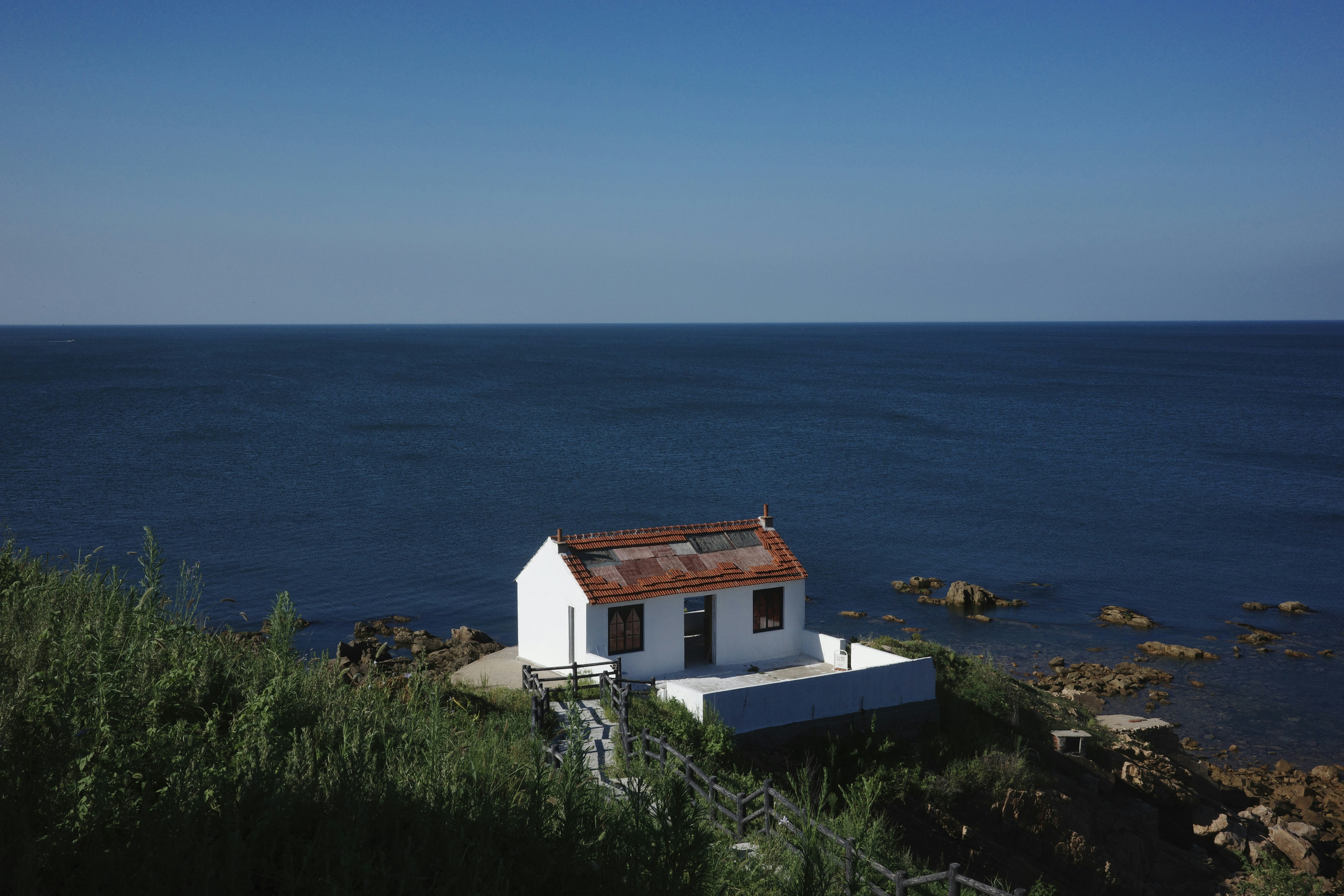 Sea-side White House Amid Coastal Cliff and Quiet Horizon