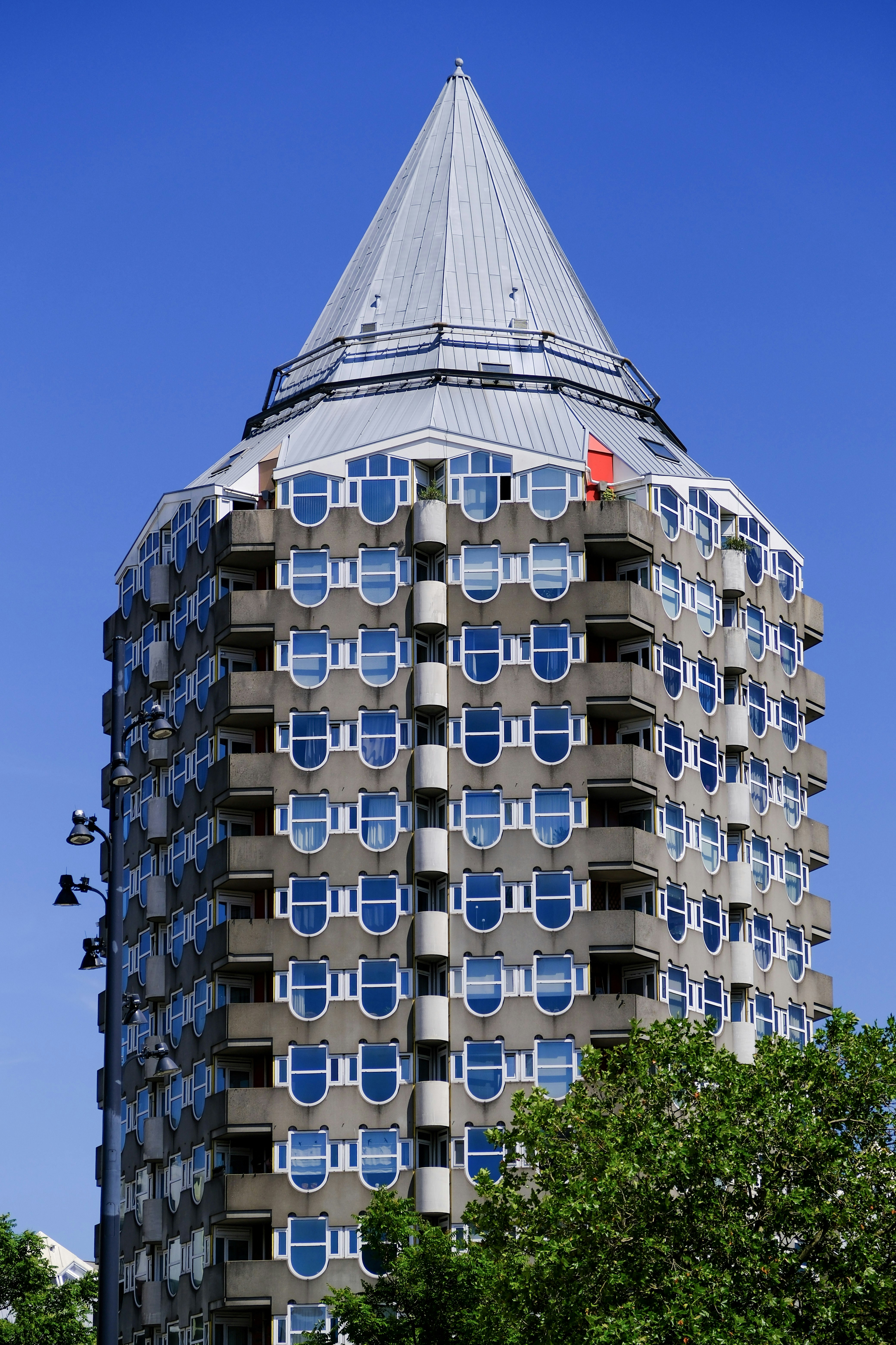 Capped by a steel spire: a stacked residential silhouette under a clear blue sky