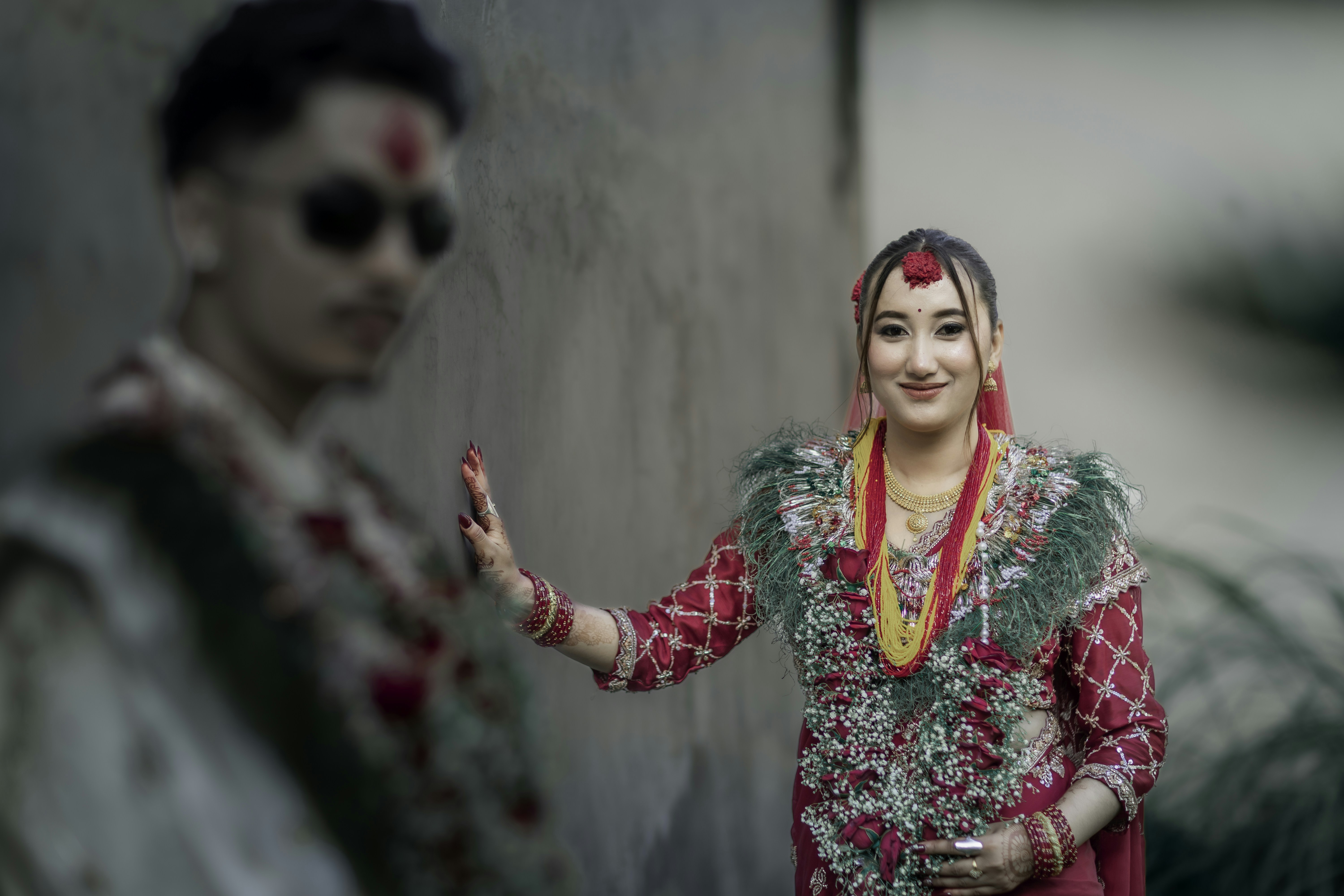Bride in vibrant ceremony attire beside a shadowed groom