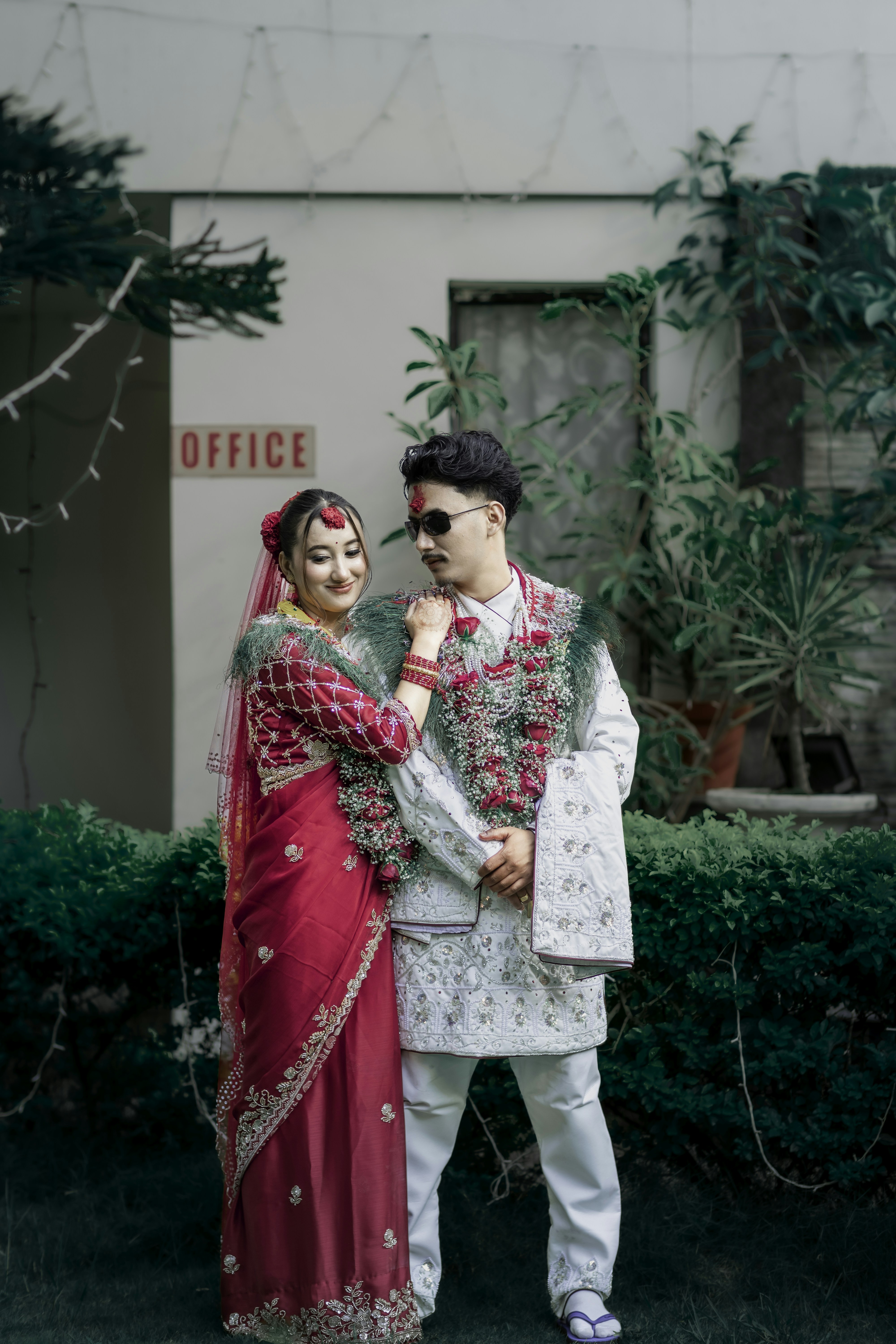 Bride and Groom in Vibrant Attire Share a Tender Moment Outside an Office