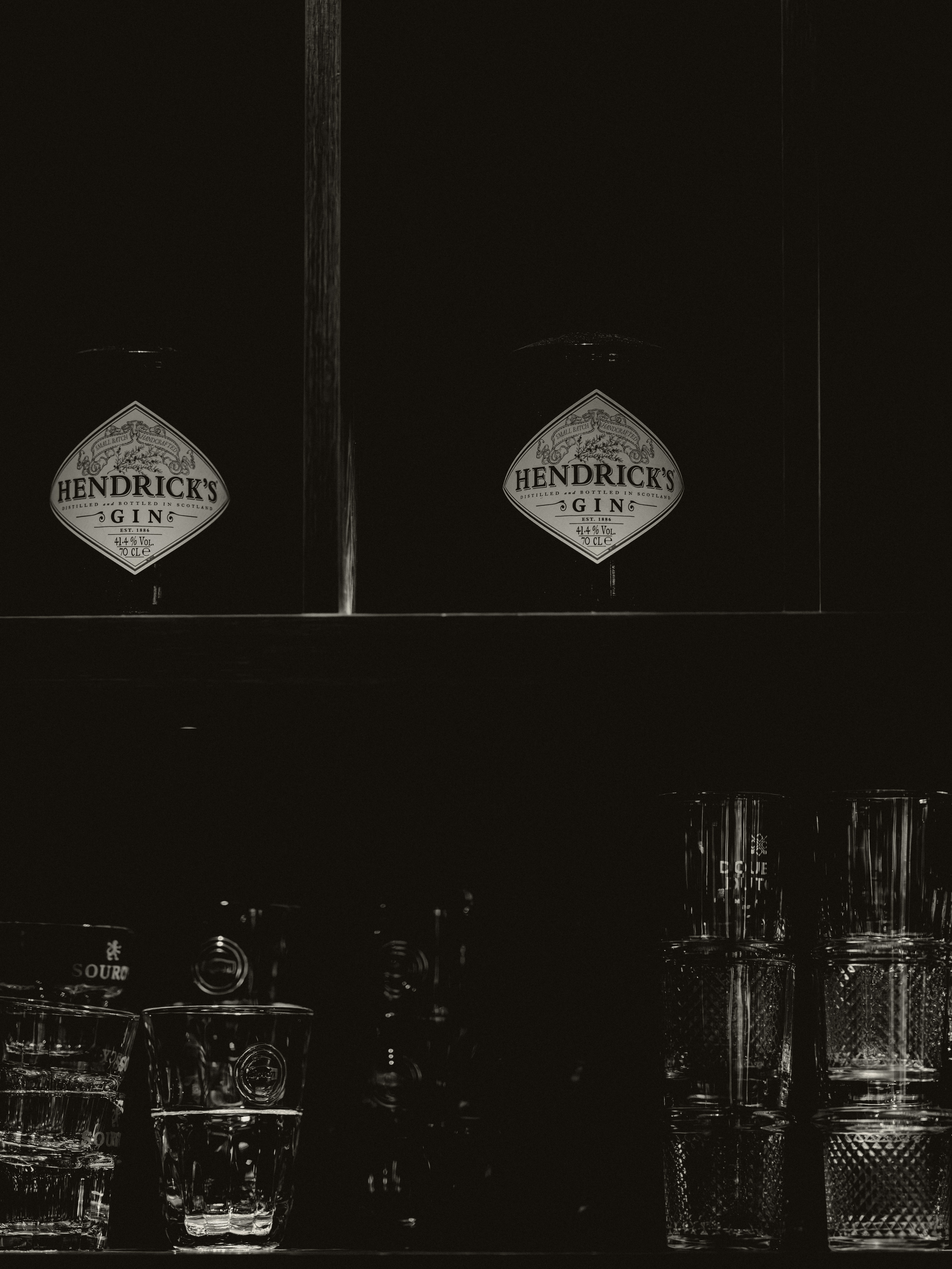 Dim Barfront: Two Hendrick's Gin Taps Above a Shadowed Shelf