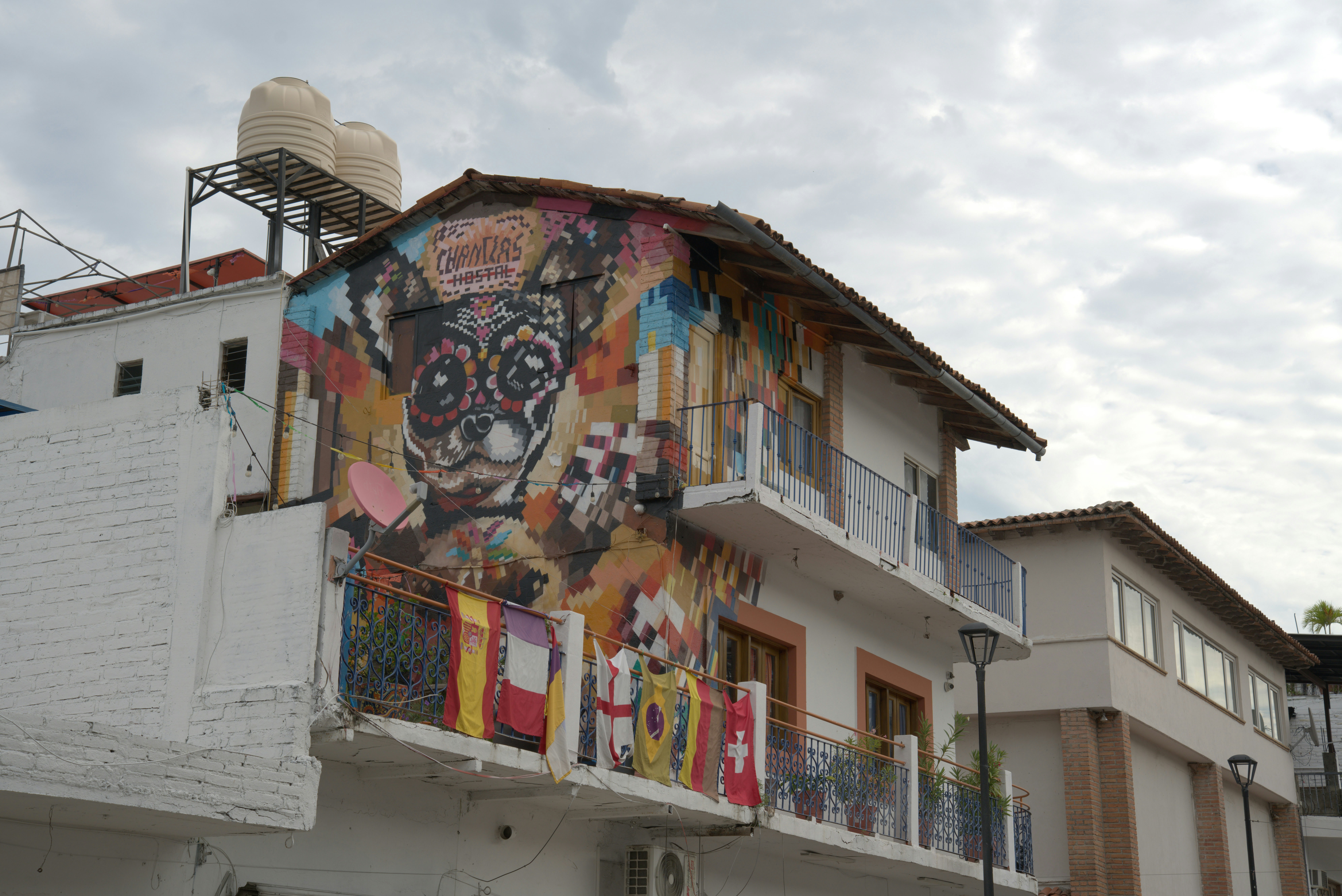 Colorful mural over a sunlit balcony transforms a quiet street