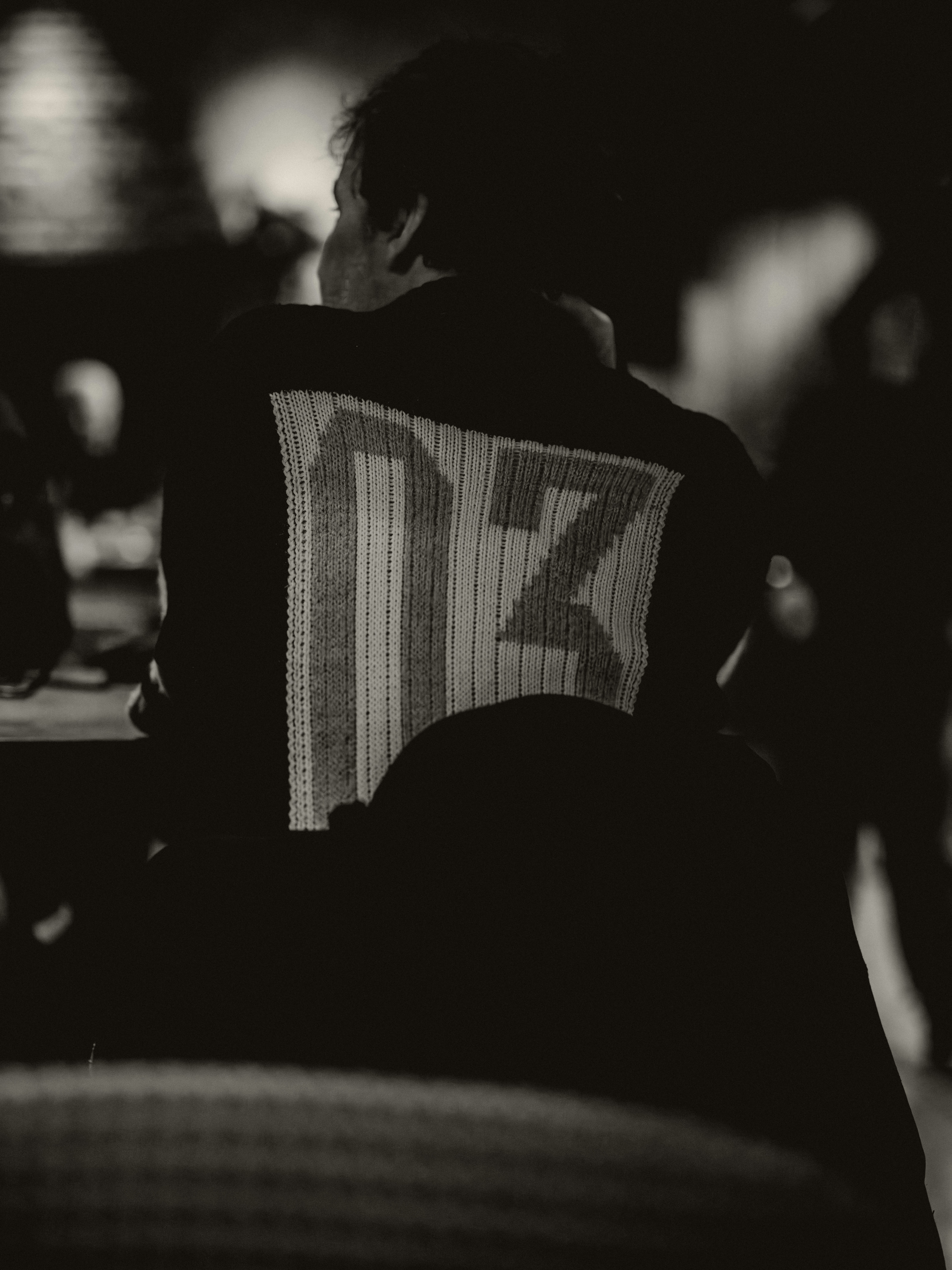 Backlit silhouette in a dim room with a knit pattern on the jacket