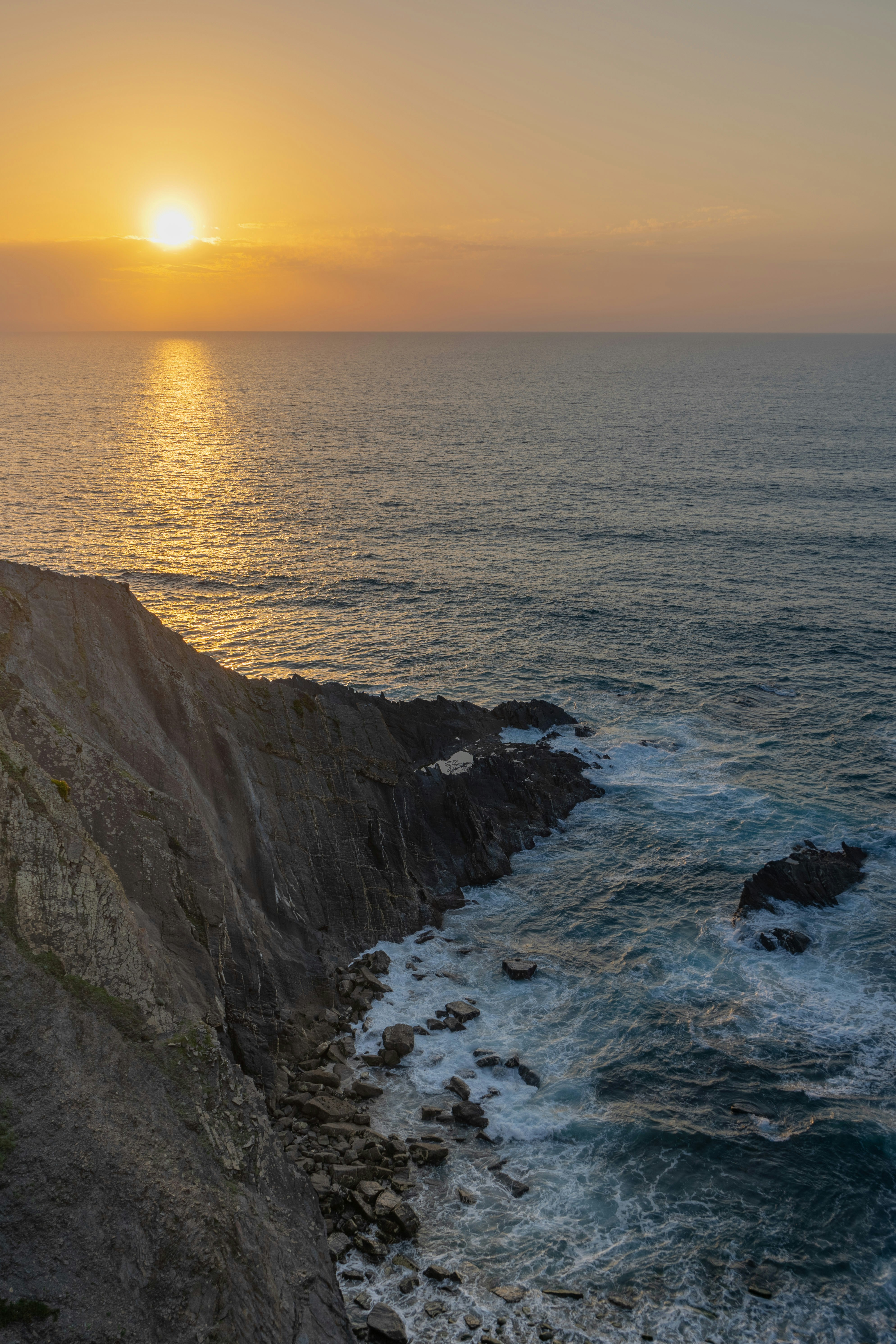 Sunlit Cliffs Meeting the Sea at Dusk