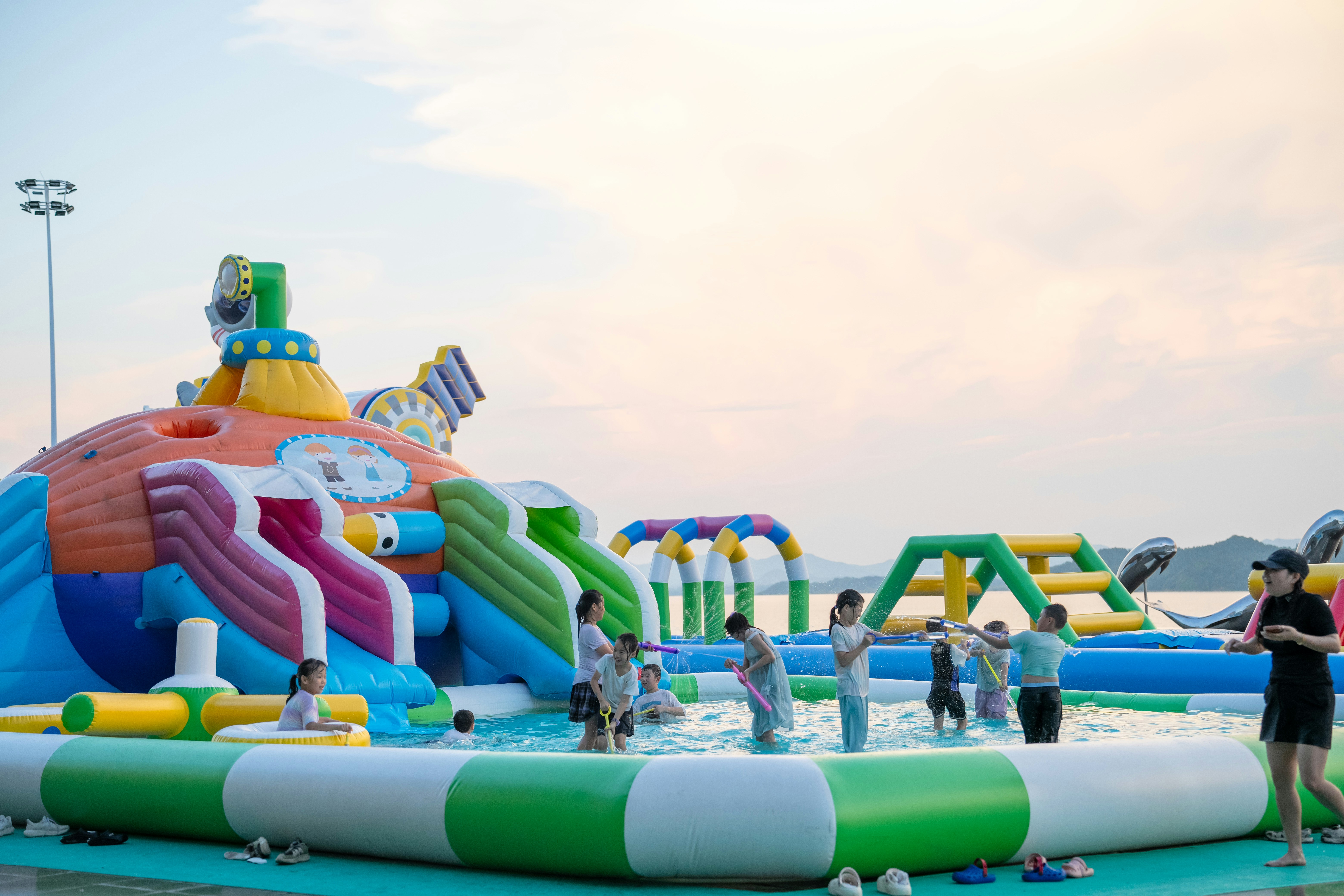 Playful Parade: Kids and Adults Conquer an Inflatable Water Playground