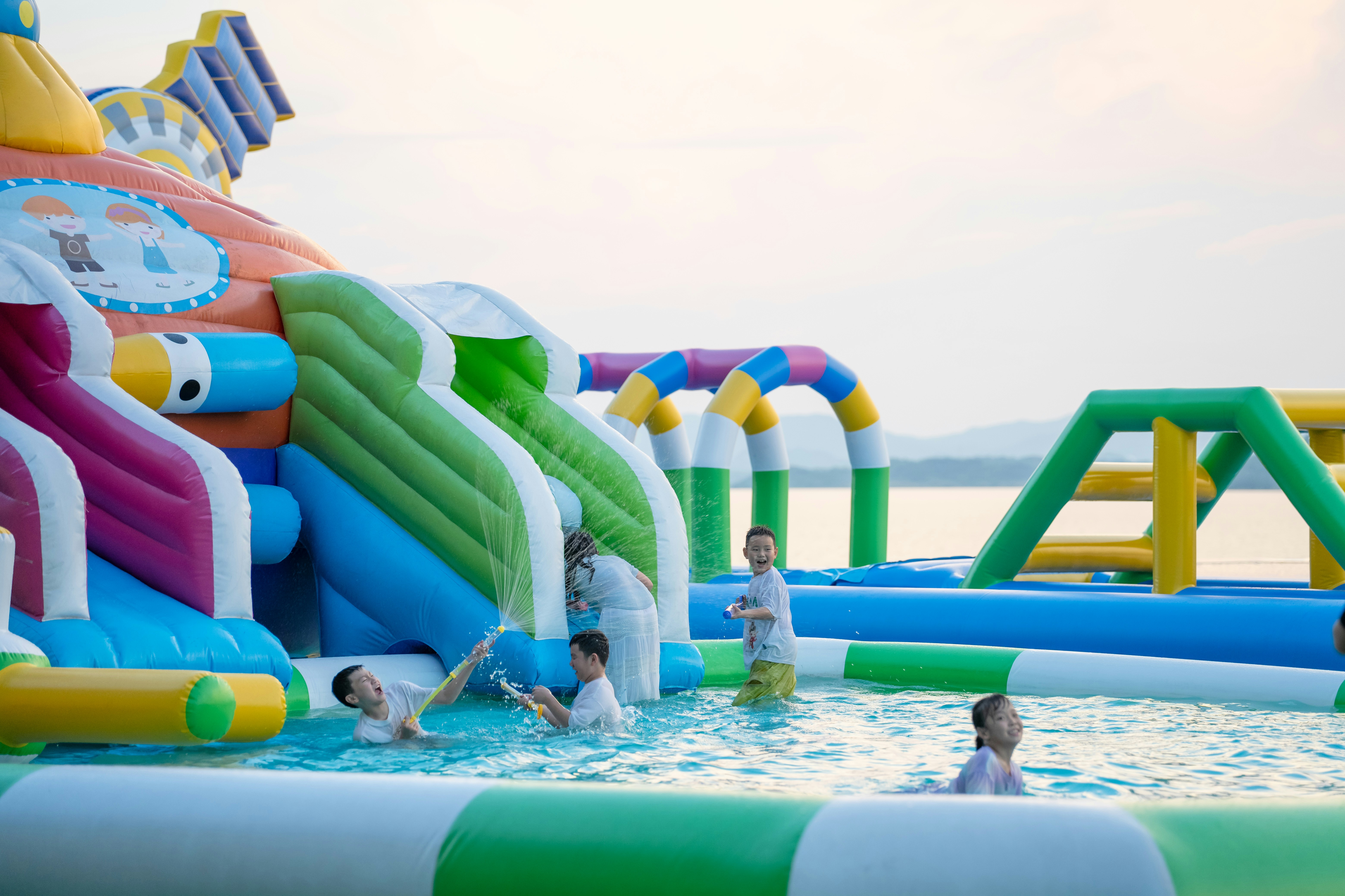 Sunlit Splash: Kids Play on a Colourful Inflatable Water Playground