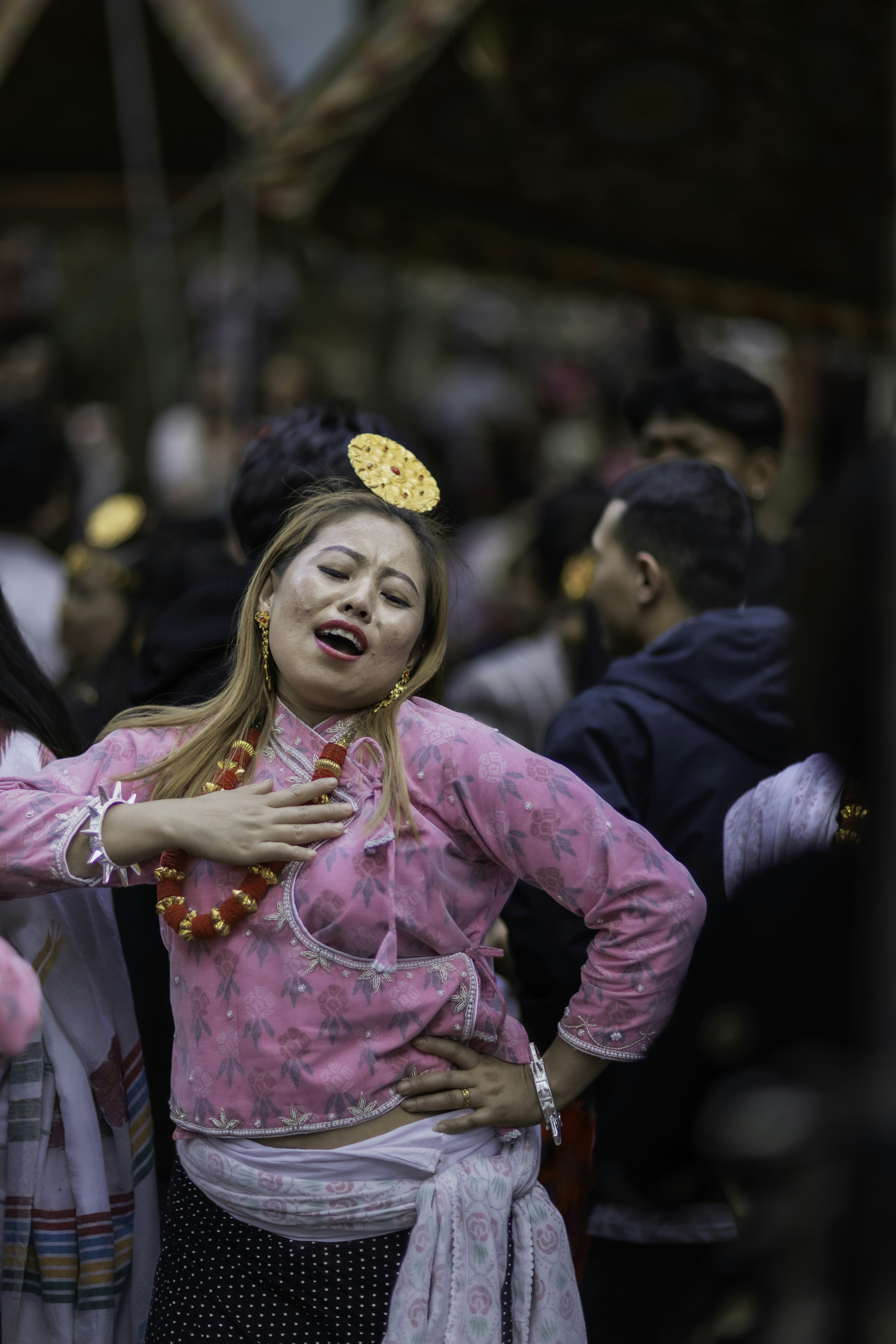 Pink-clad dancer with expressive pose amid festive crowd
