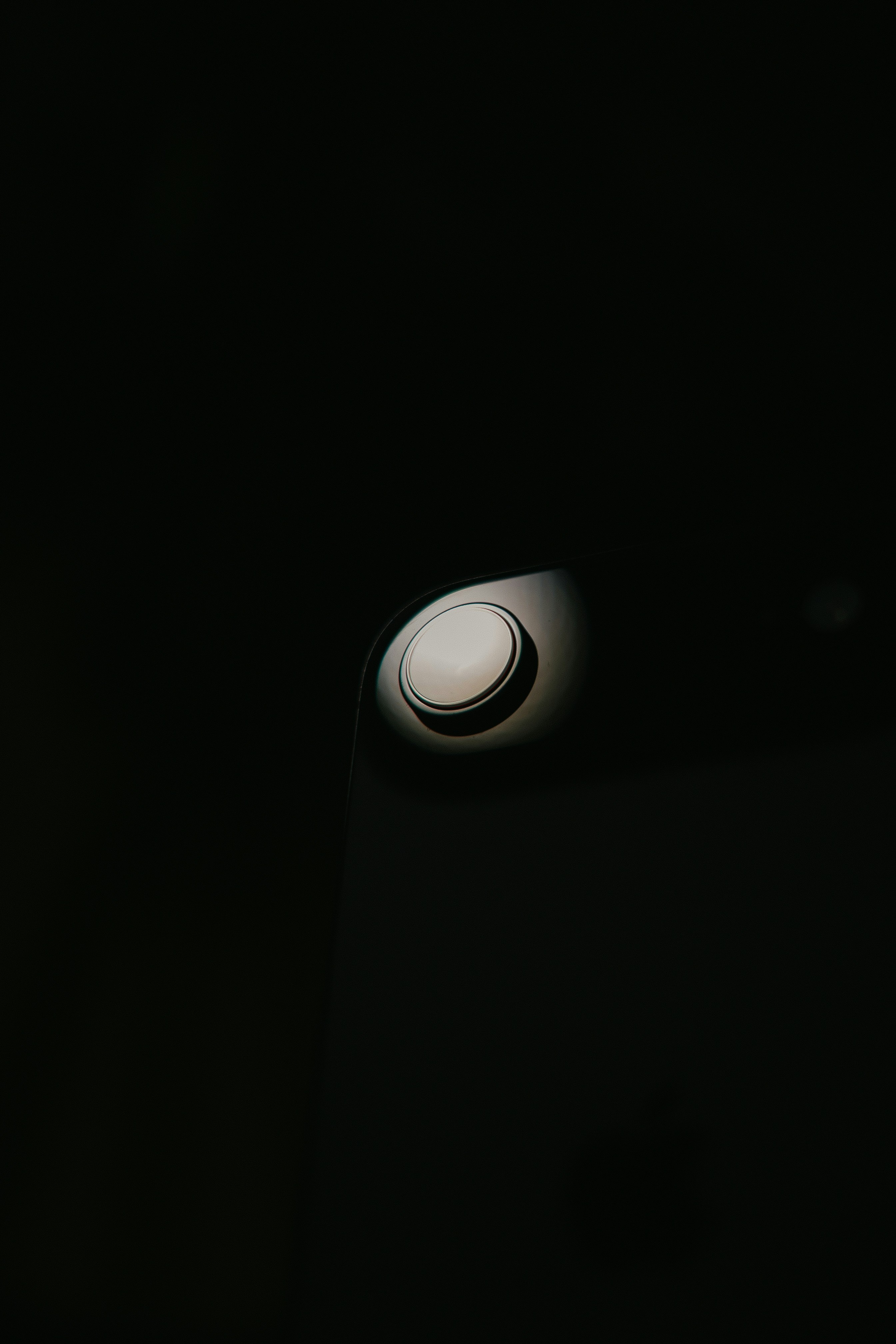 Hidden Button: Minimalist Close-Up of a Metal Power Button in Low Light