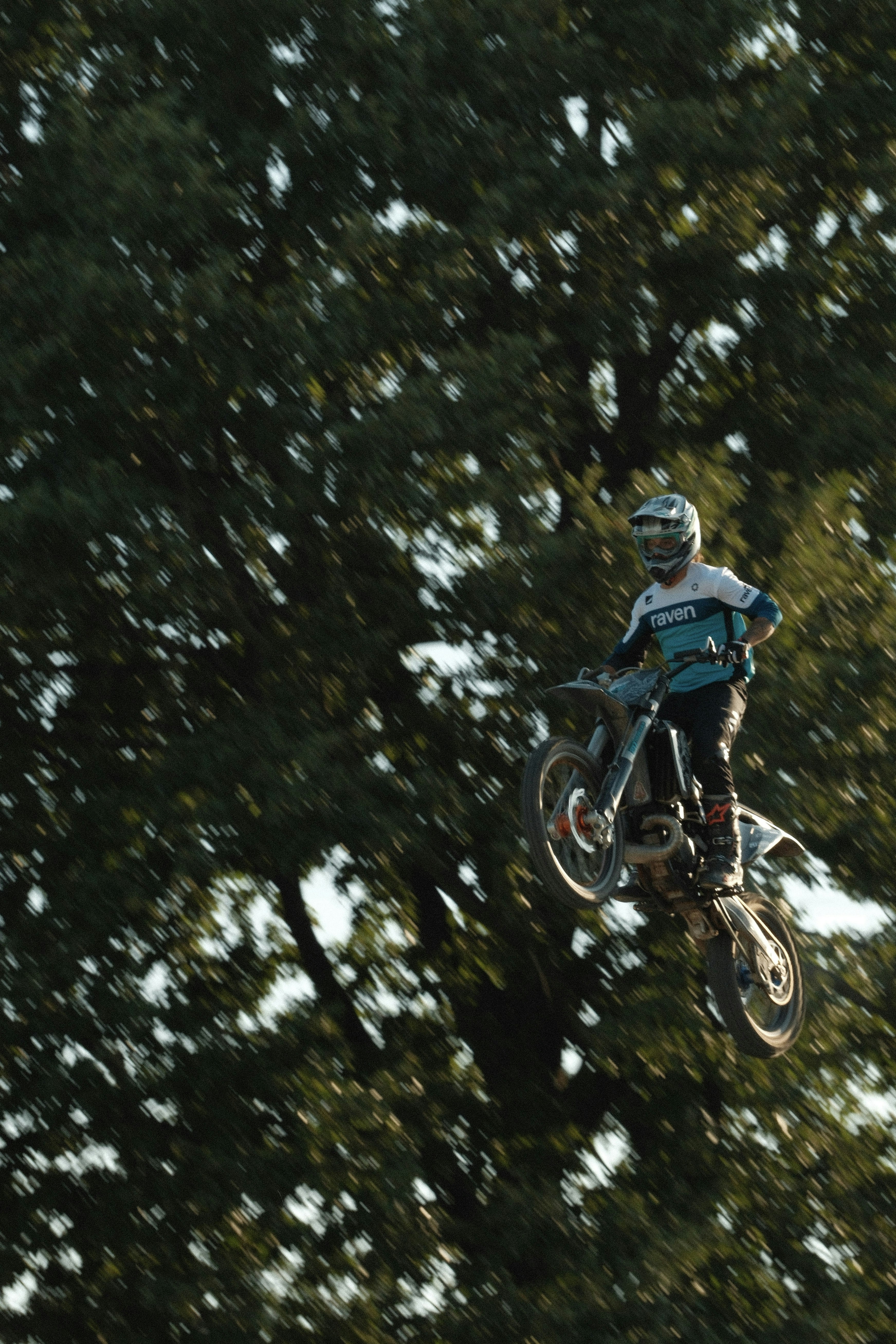 Mid-Air Rider: A Motocross Moment Captured Against a Canopy of Trees