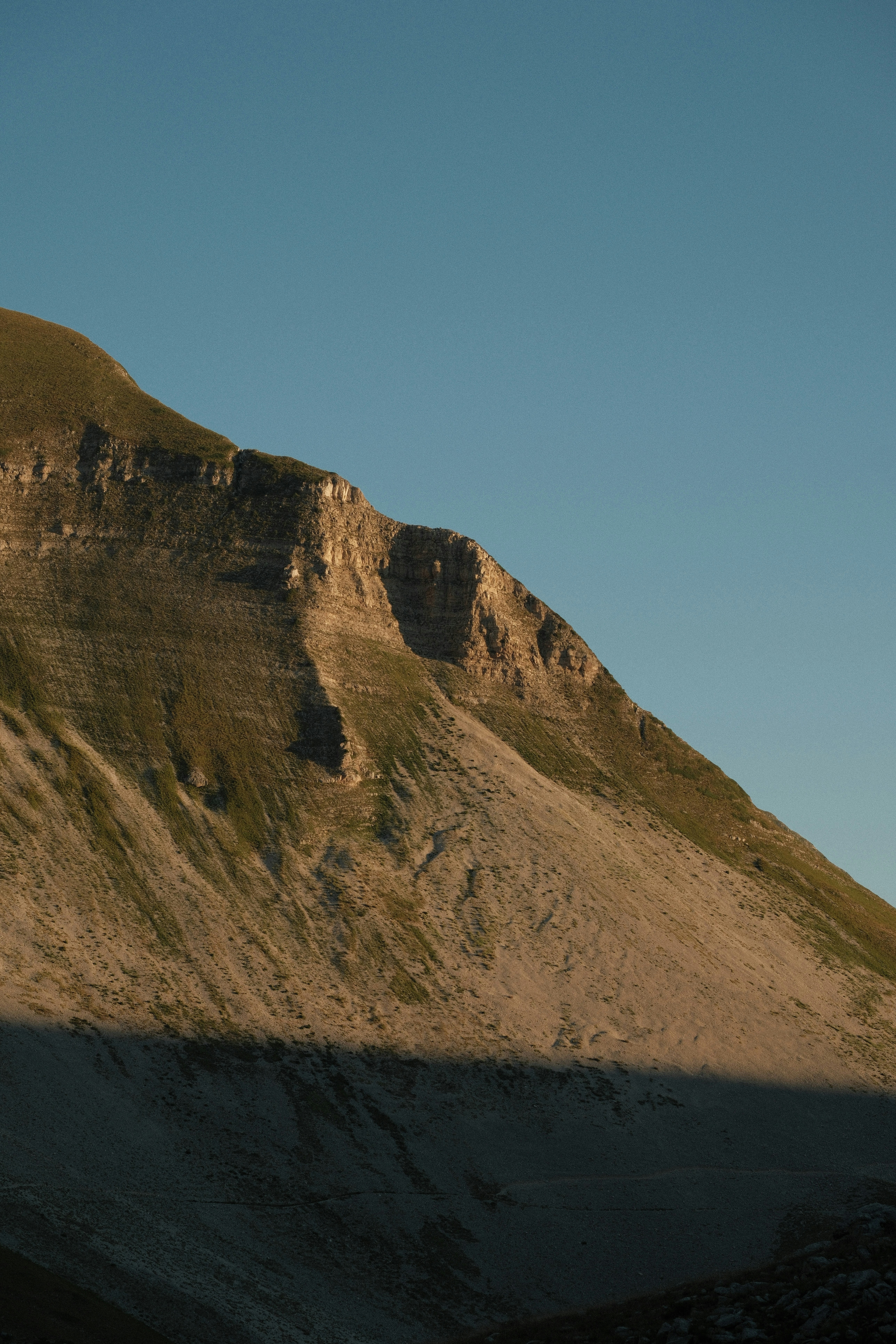 Golden Ridge at Dusk: Sunlit Cliff Face and Shadowed Slope