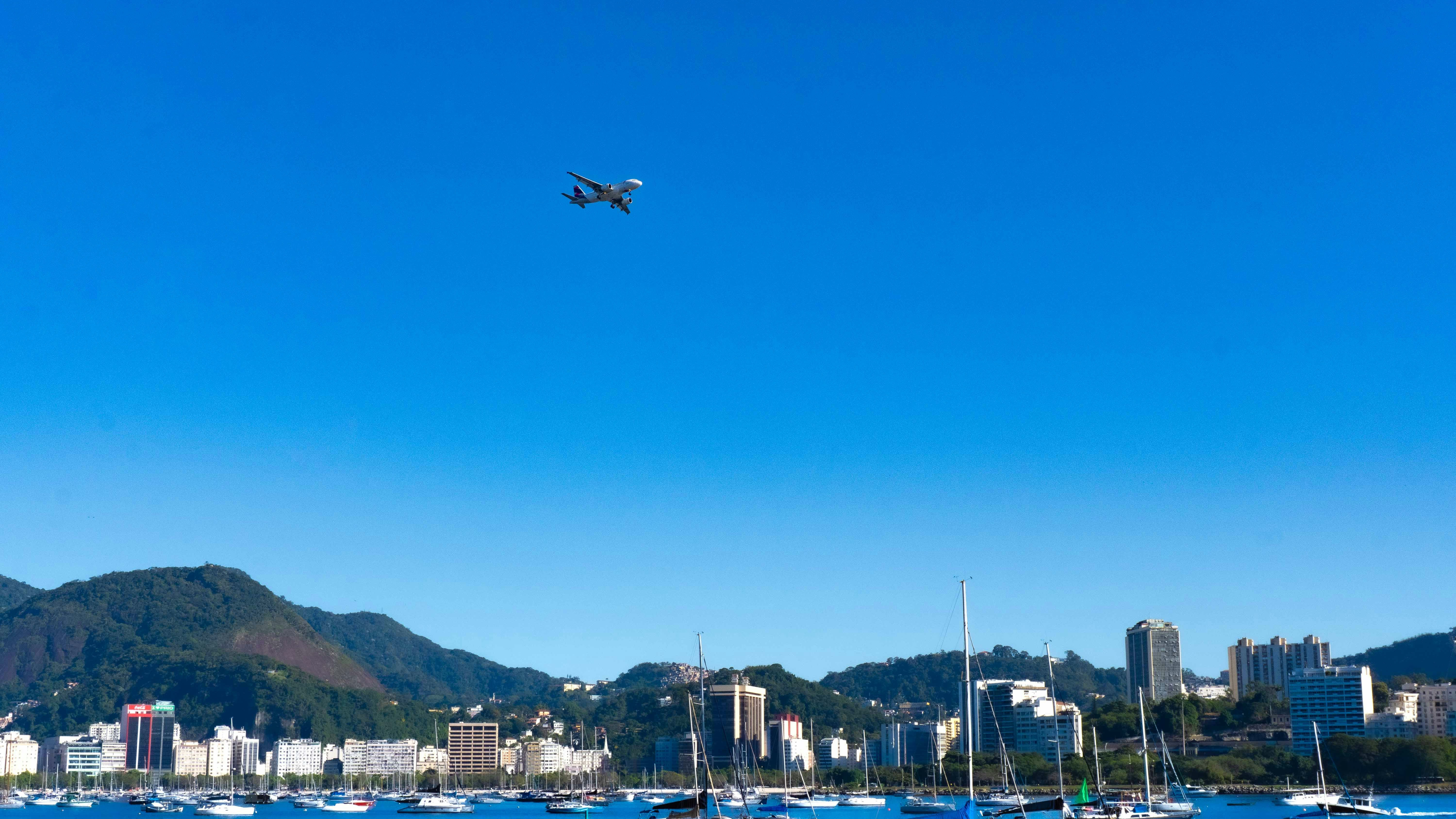 Plane Above a Seaside Cityscape at Clear Sky